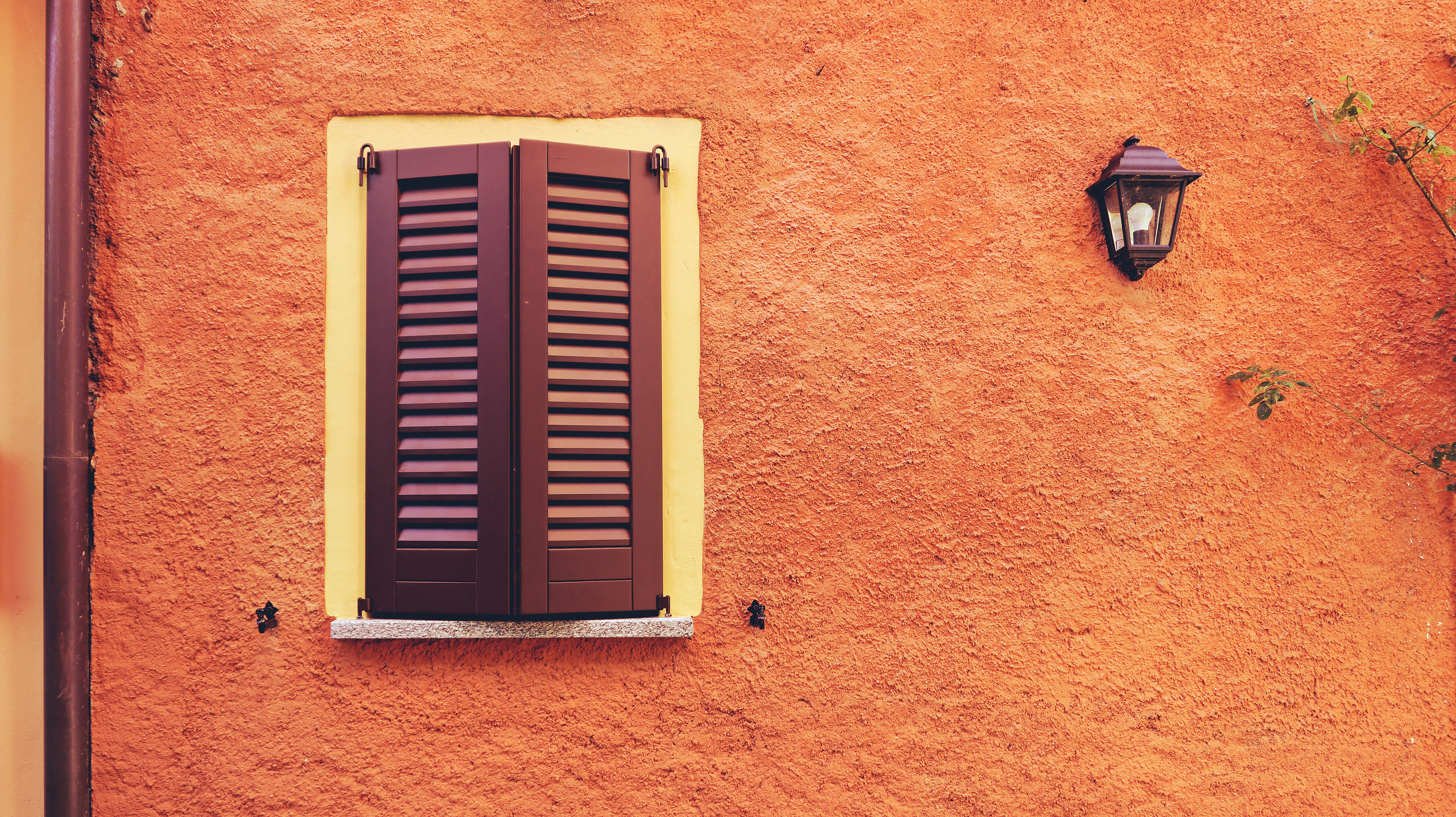 Amber Facade: a shuttered window on a sunlit terracotta wall