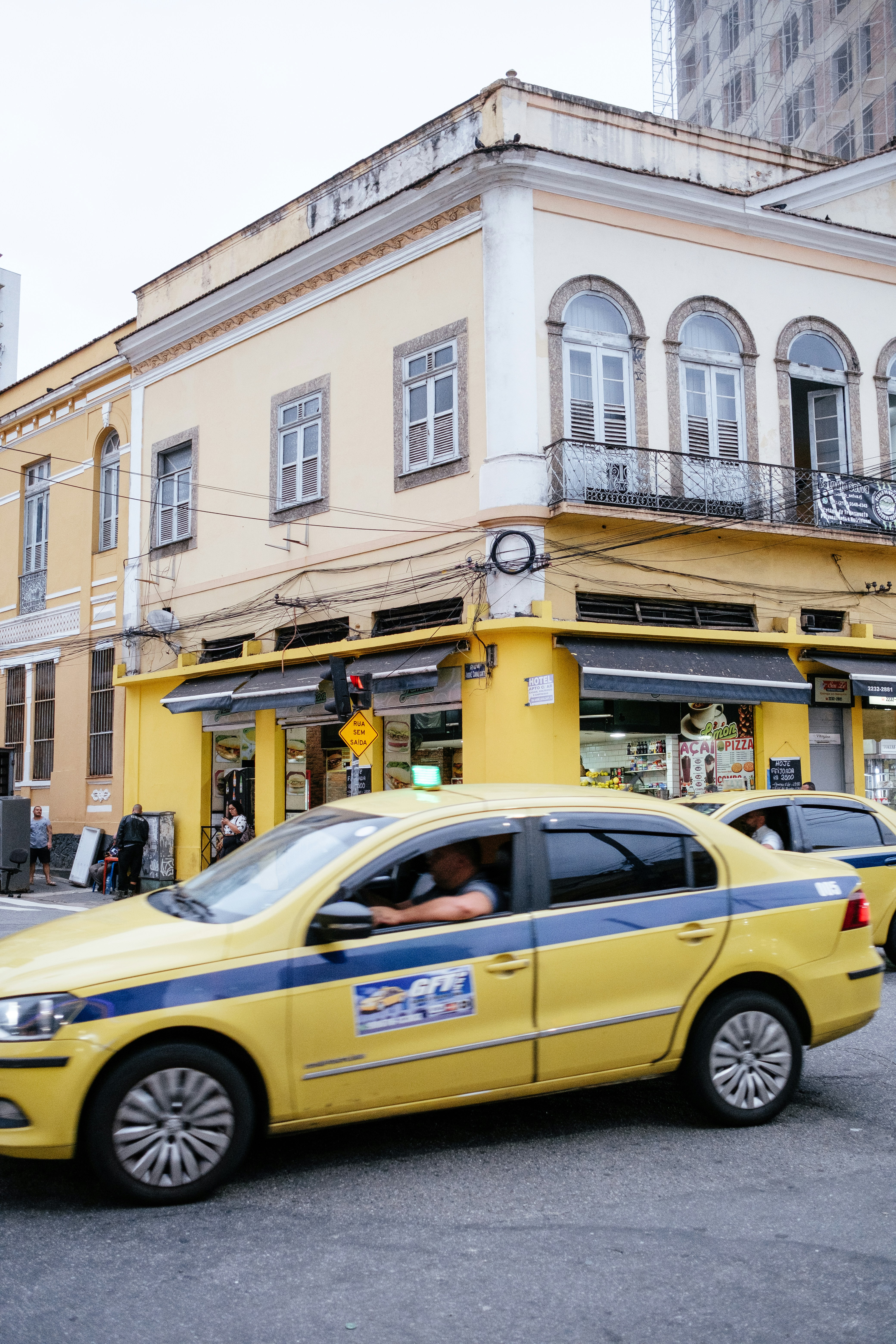 A yellow taxi cab driving down a street next to tall buildings photo ...