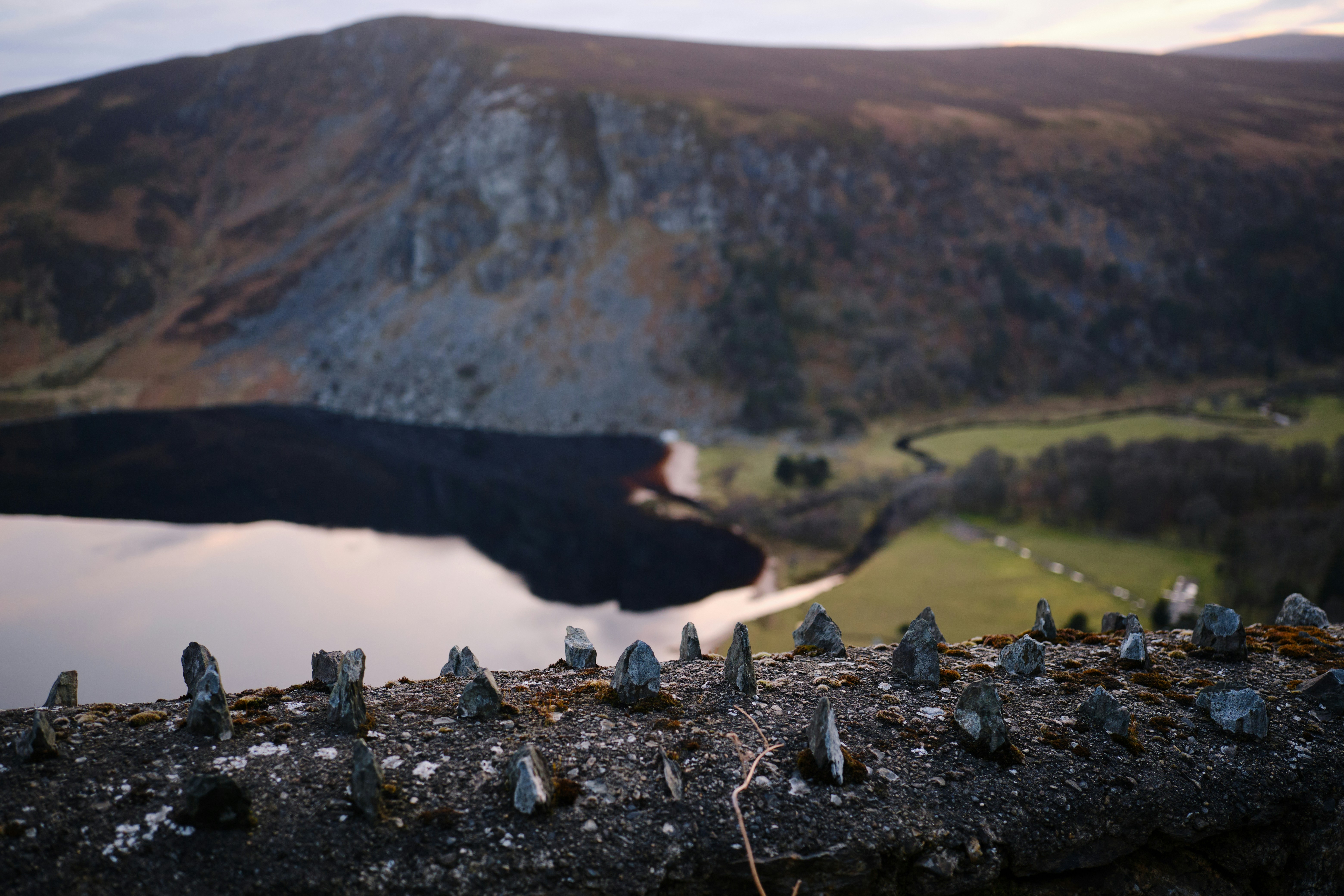 Rocky foreground overlooking Lough Tay with rolling hills and a serene lake in the background.