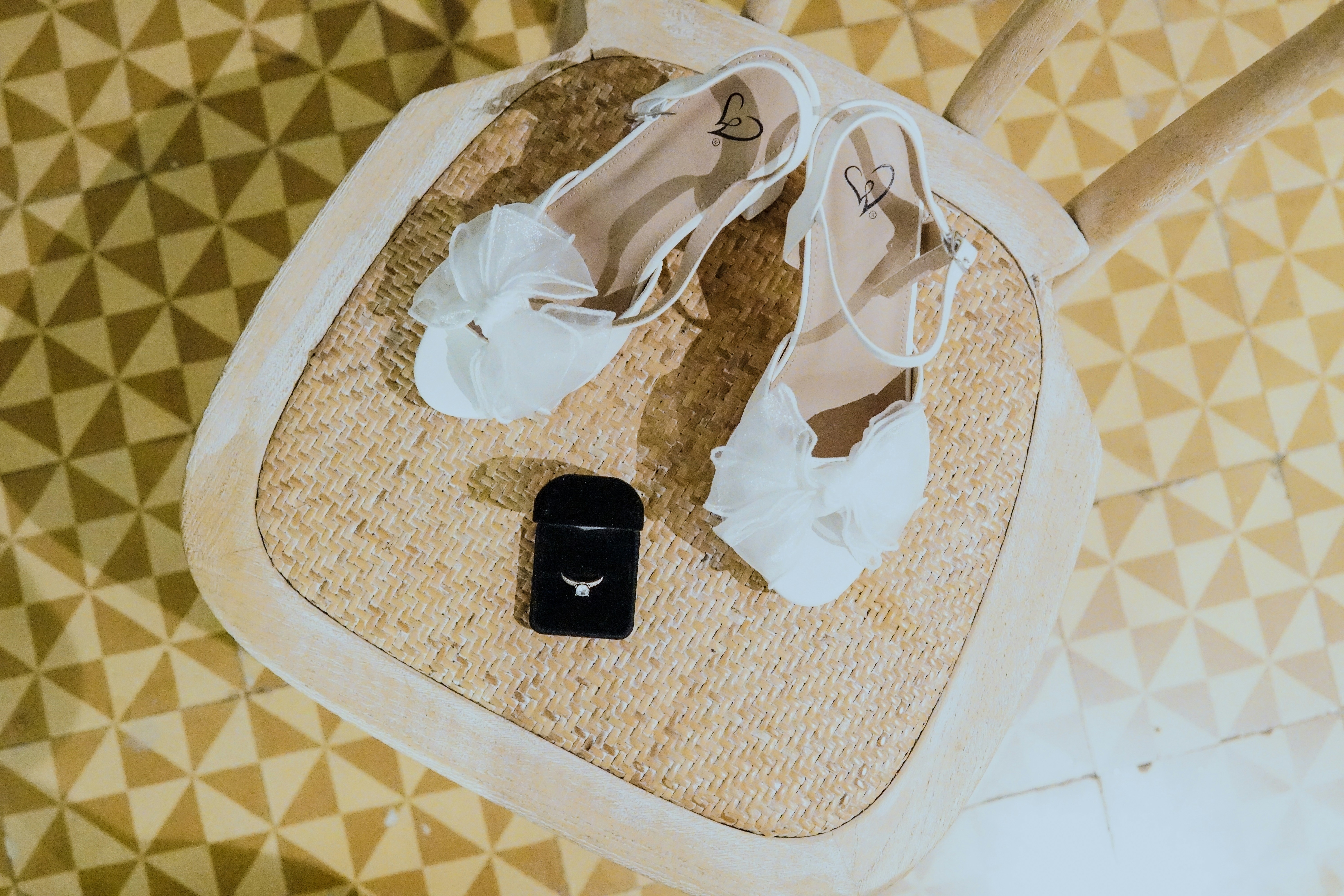 Contrast on a woven chair: white sandals cradle a tiny black box