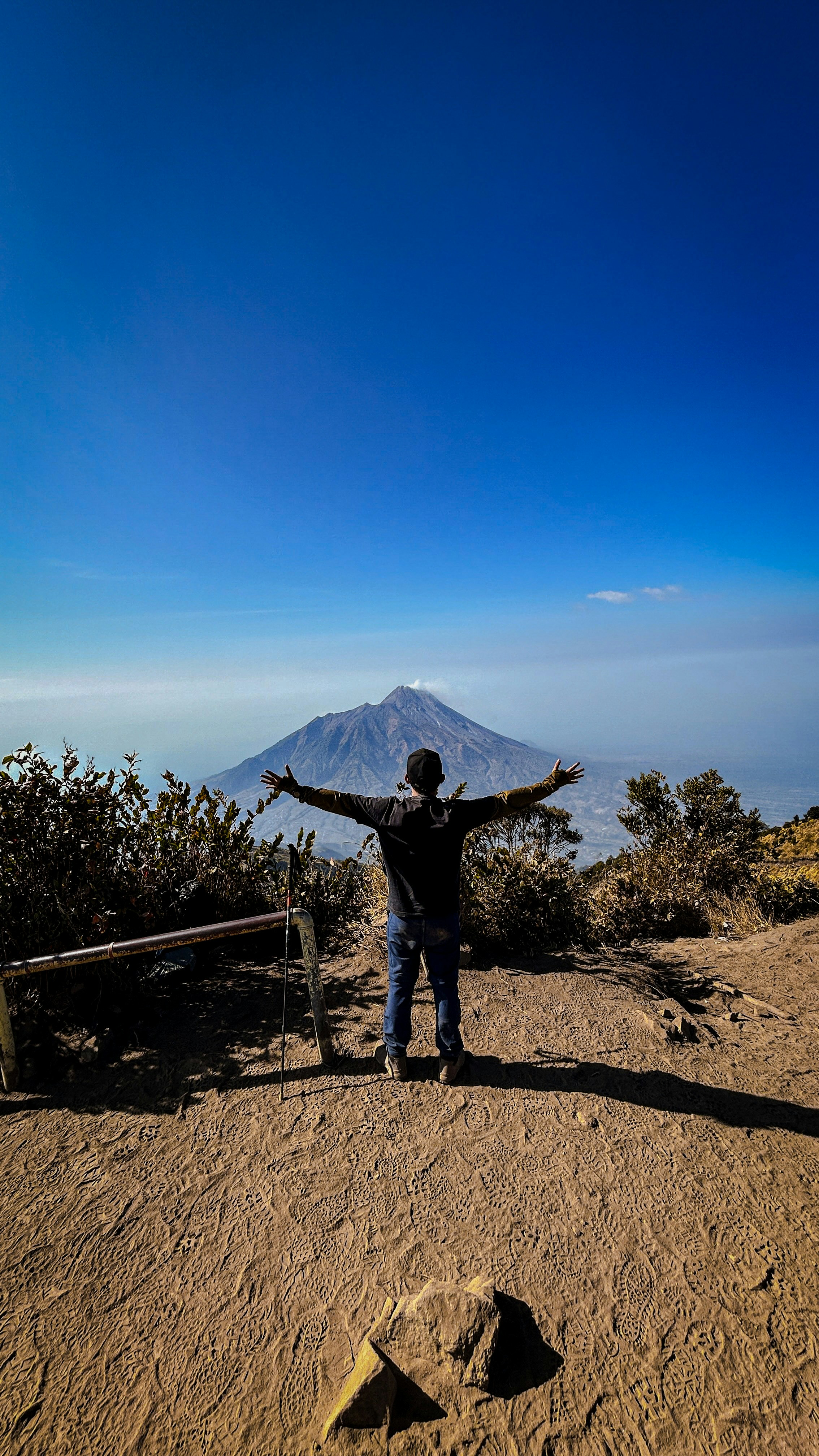 Arms Wide at the Overlook: A Hiker Faces the Solitary Volcano