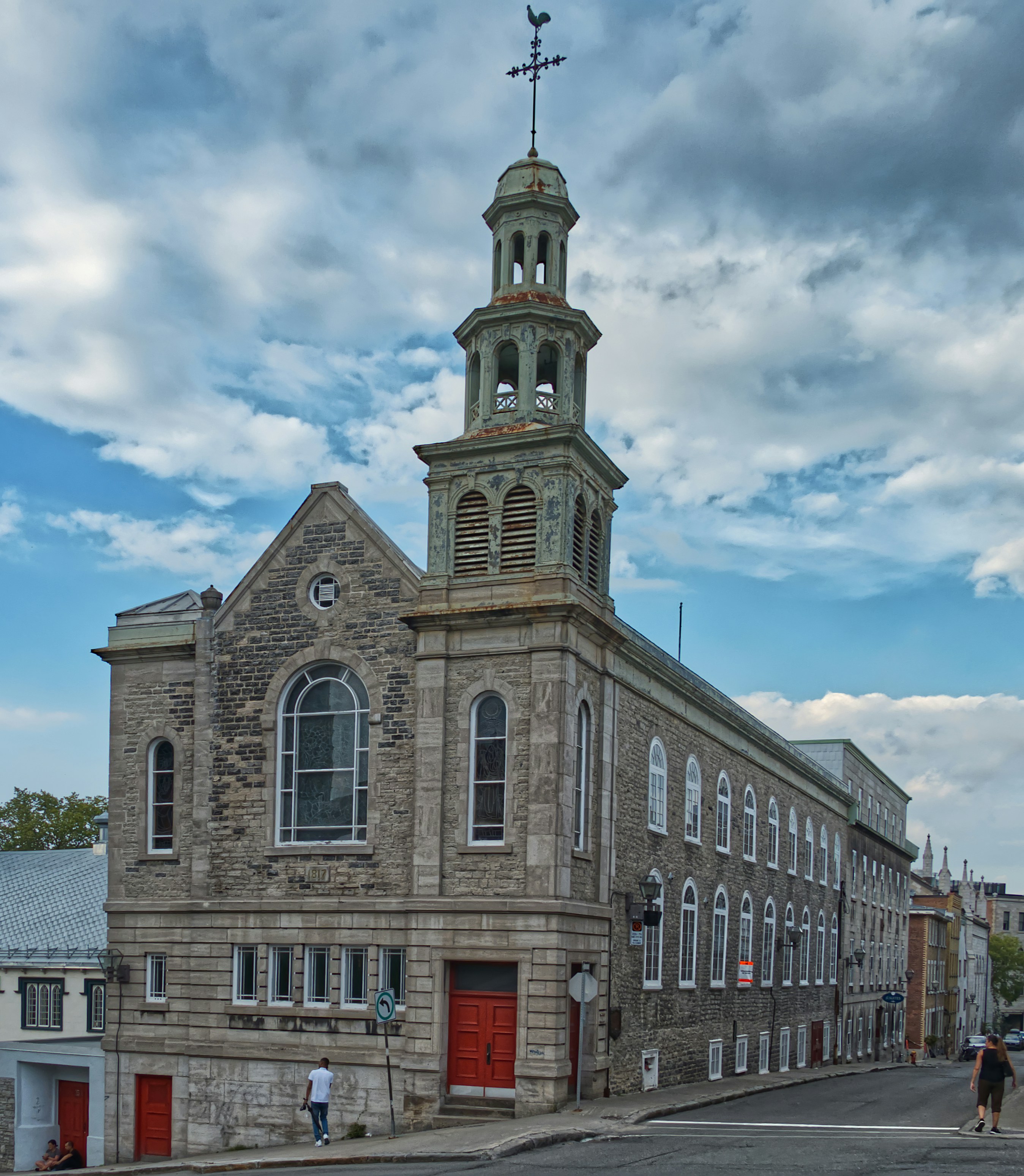 Stone Sentinel with Red Doors: A Church Stepping Along a Quiet City Street