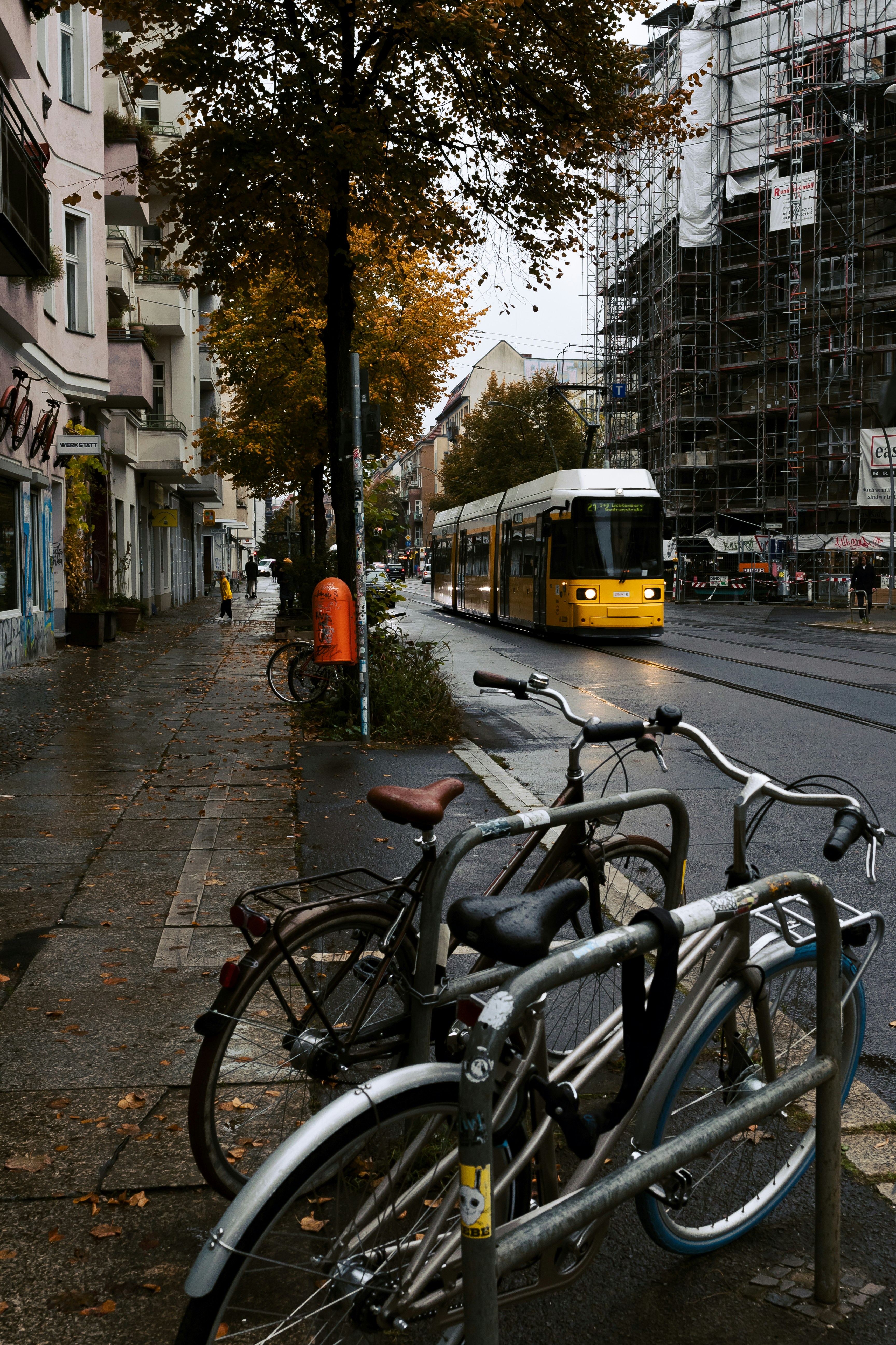Yellow tram cutting through a rainy urban street