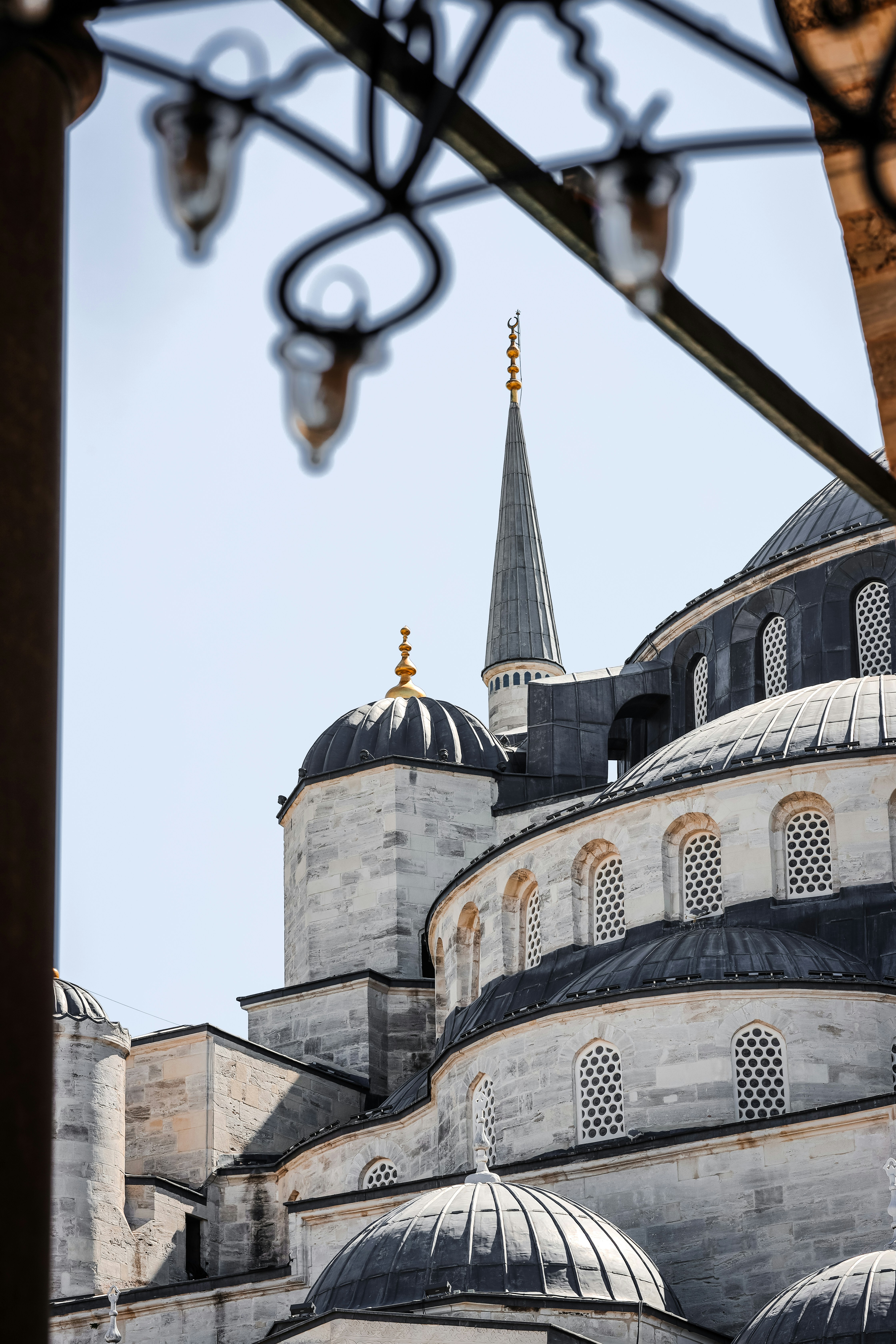 Minarets and Arches: A Mosque Skyline Framed by Wrought-Iron Patterns