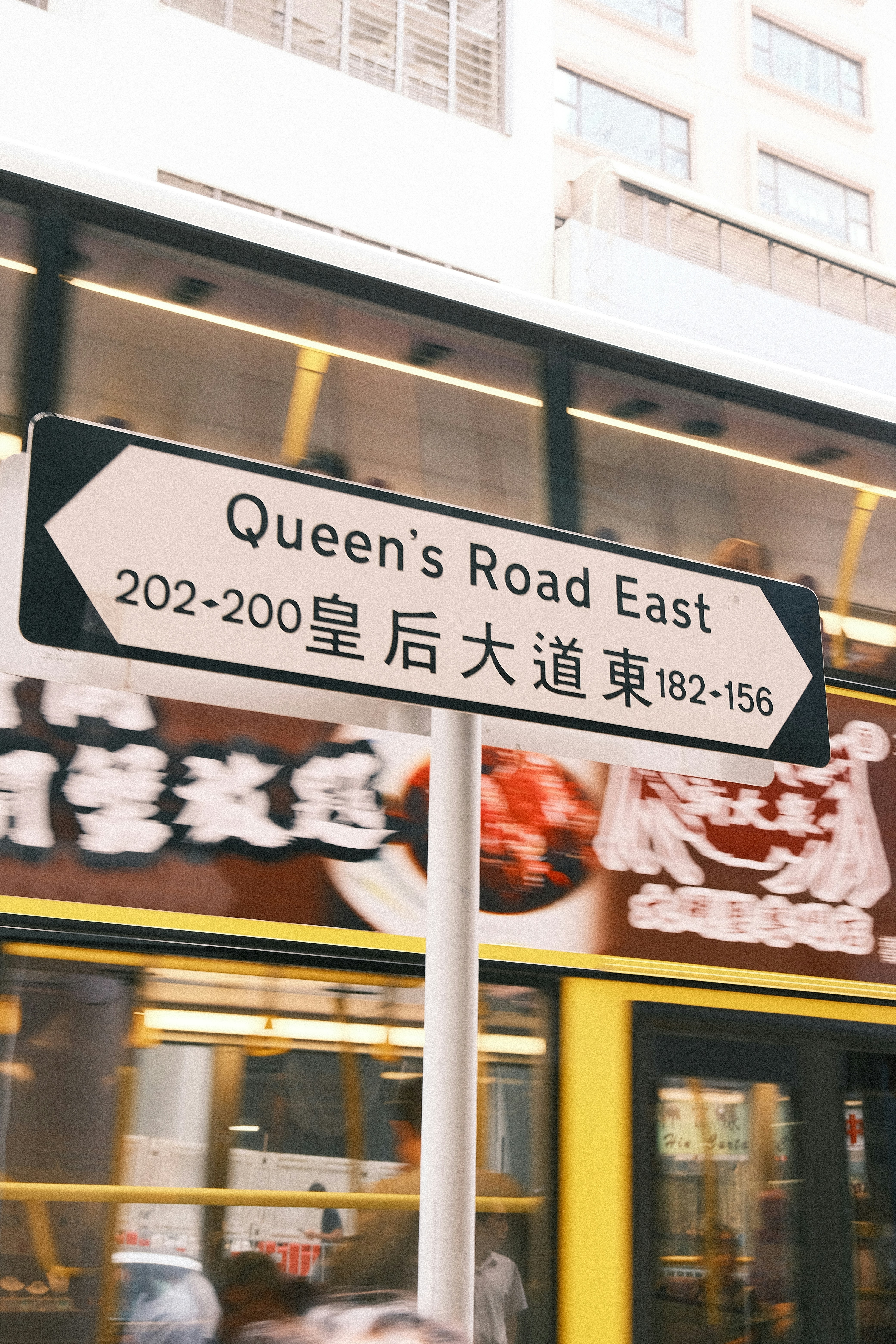 Queen's Road East Signpost Framed by a Blur of Neon Hong Kong Street