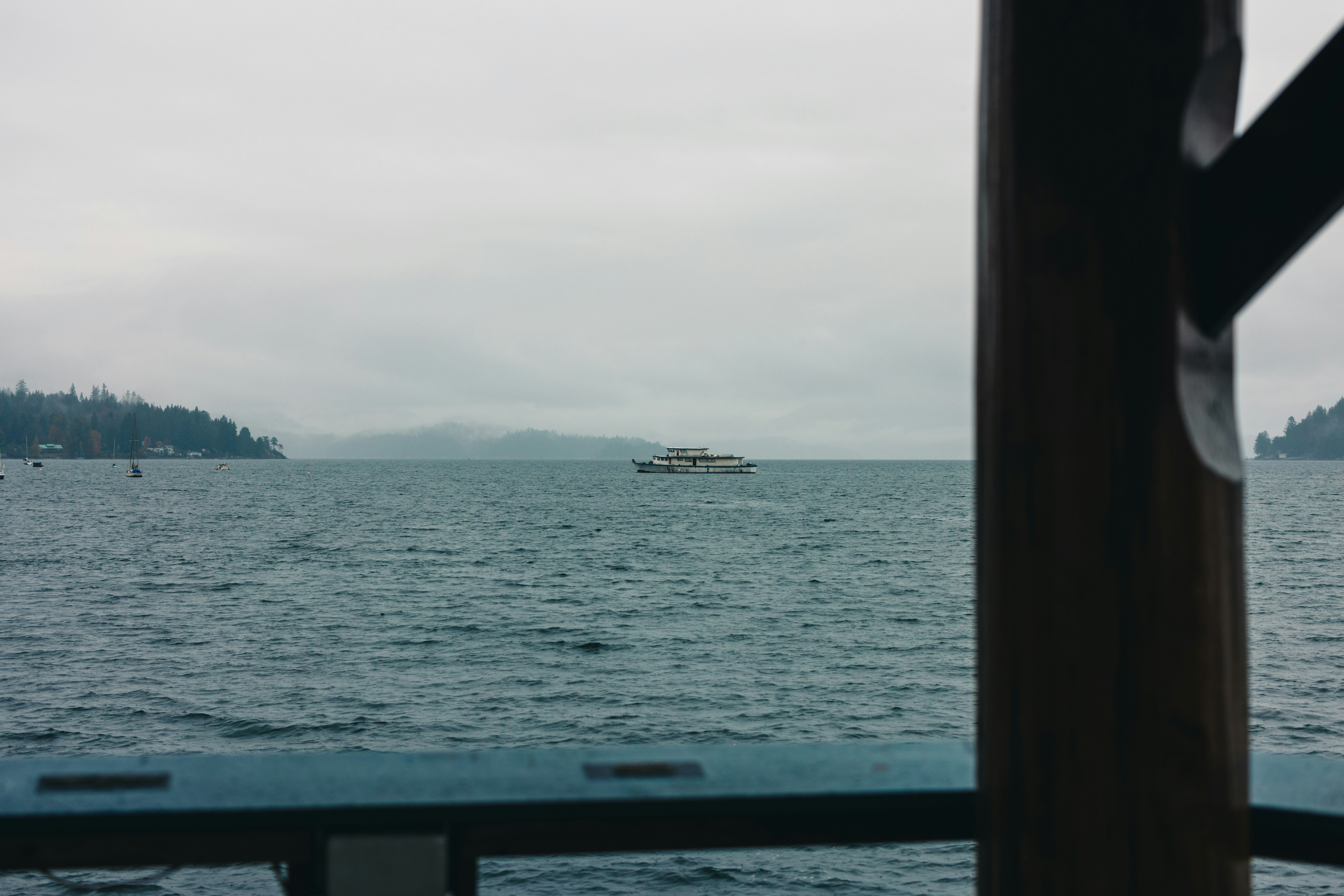 Distant Ferry on a Quiet Gray Sea, Framed by Pier Railings