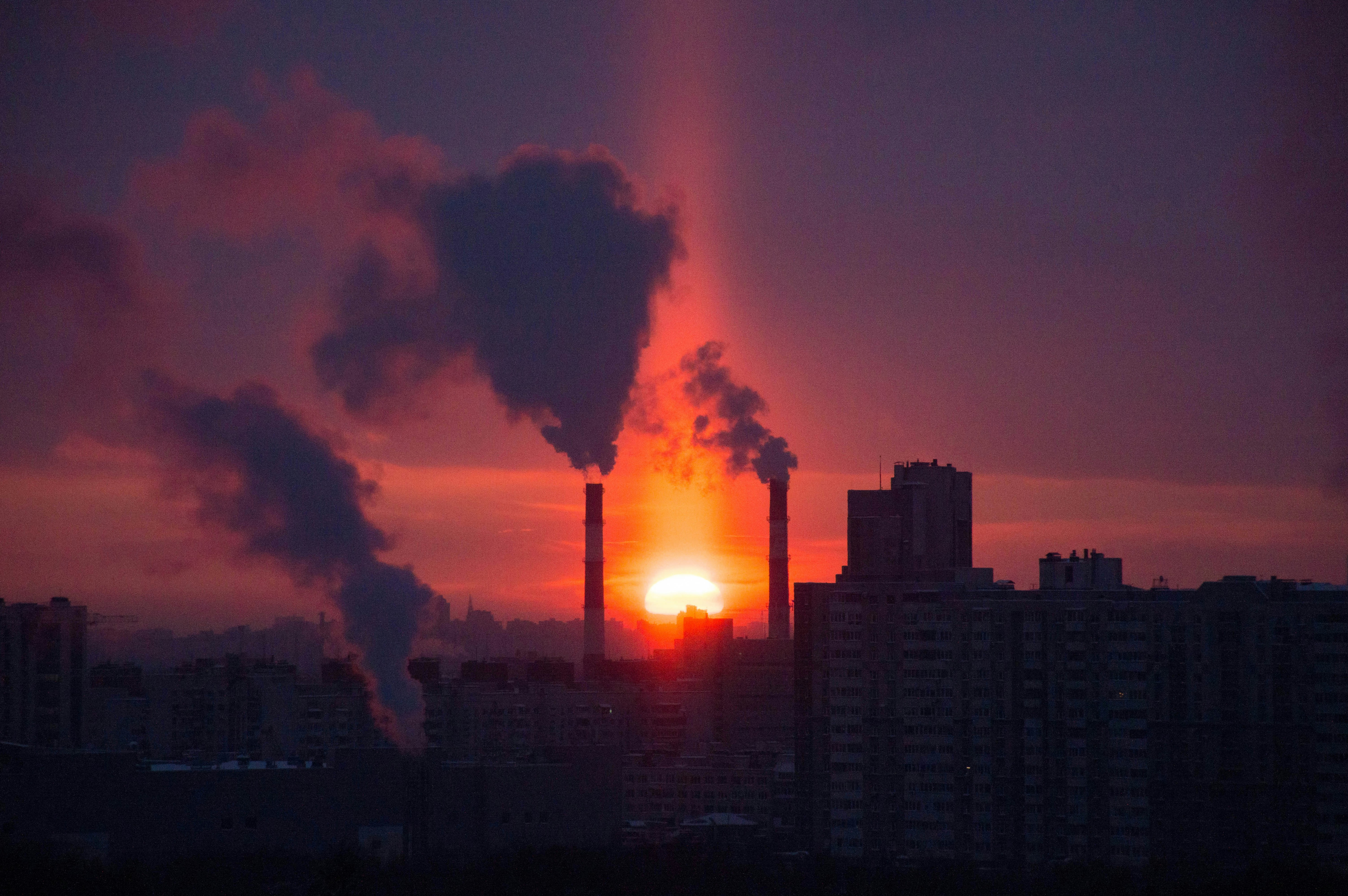 The sun is setting behind smoke stacks in a city photo – Free City ...