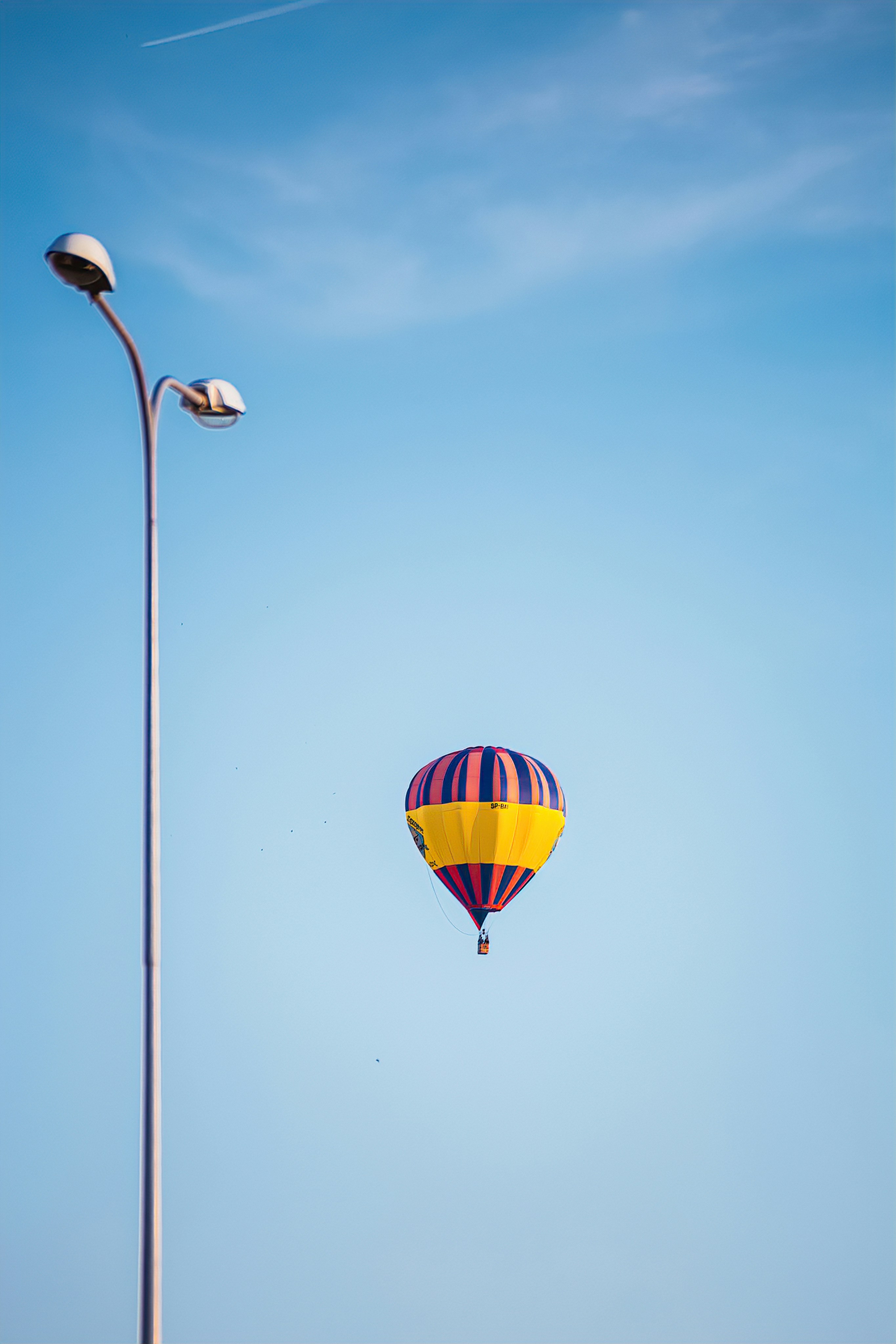 Azure Sojourn: A Hot Air Balloon Gliding Past a Quiet Streetlamp
