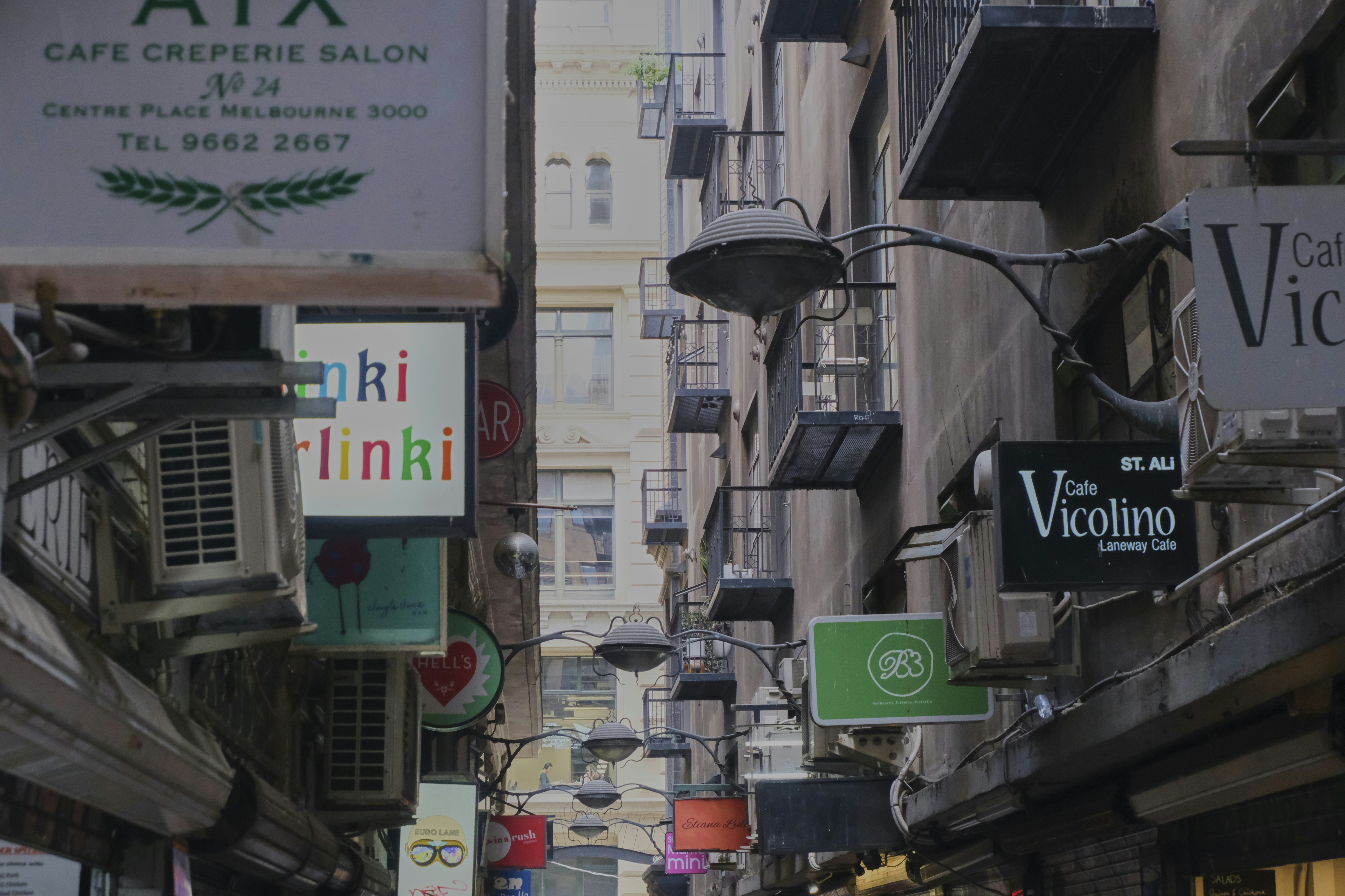 Sign-Lined Alley: A Narrow Urban Canyon of Shopfronts and Balconies