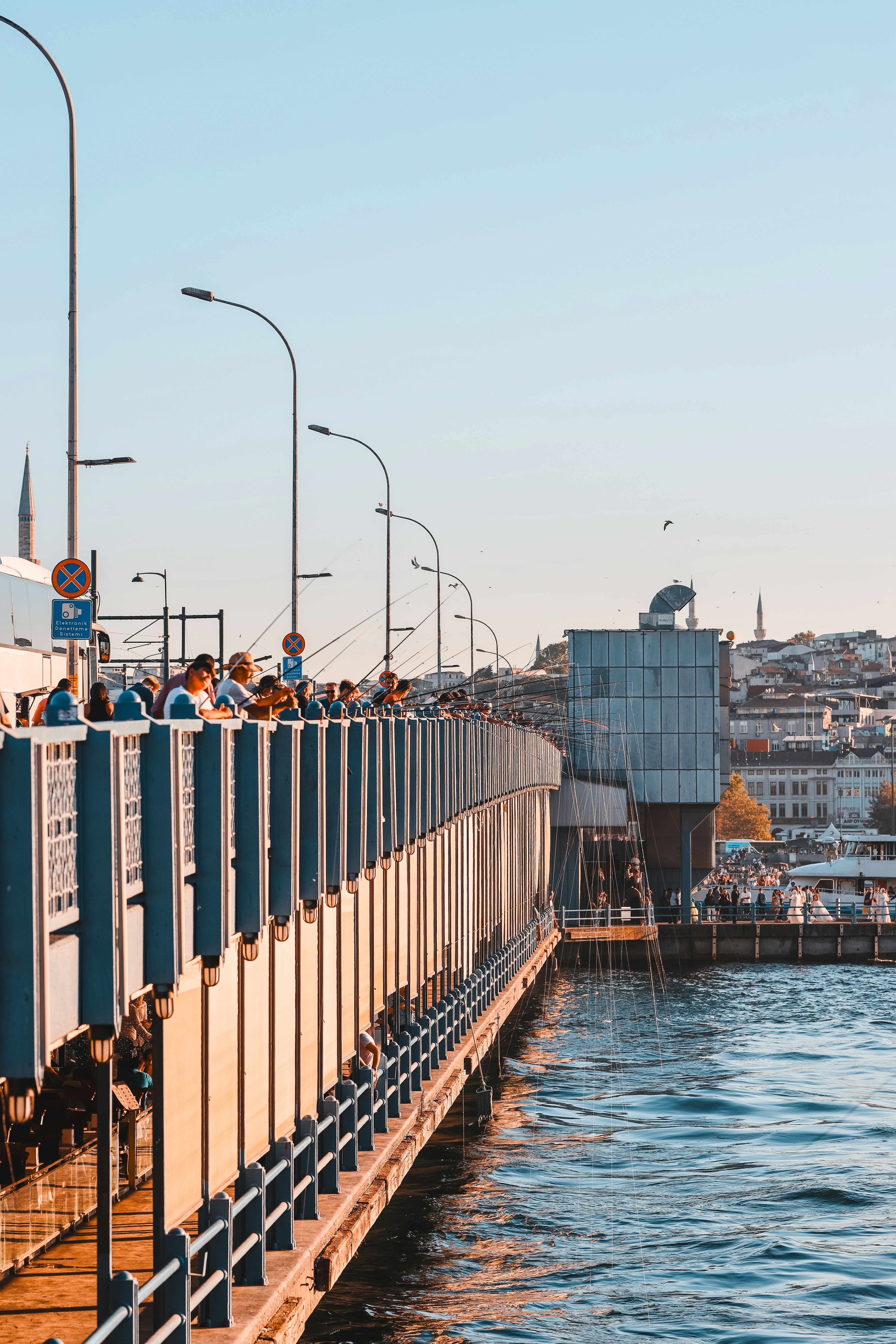 Golden Hour Crowd Along a Waterfront City Bridge