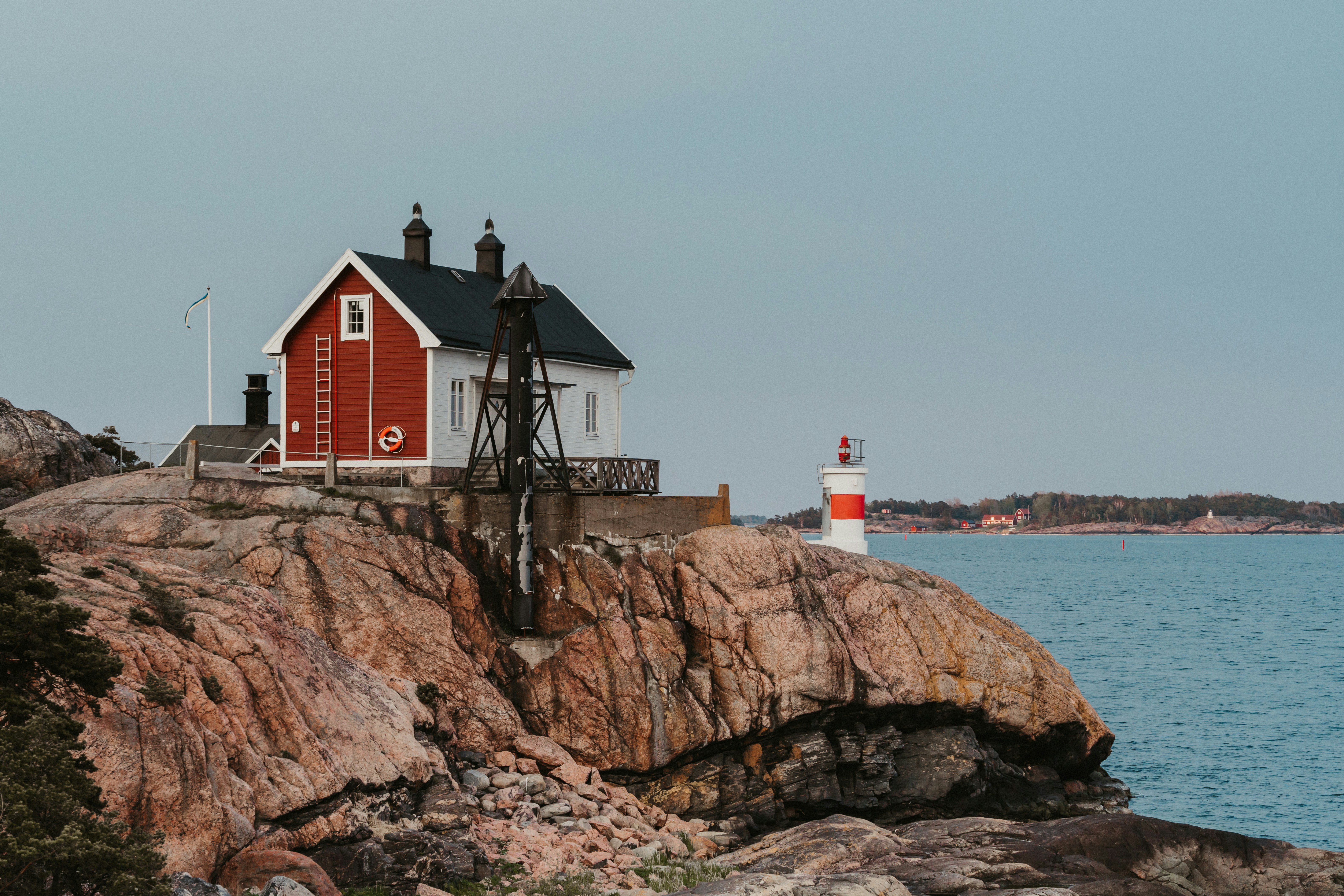 Un phare rouge et blanc au sommet d’un rocher à côté de l’océan photo ...