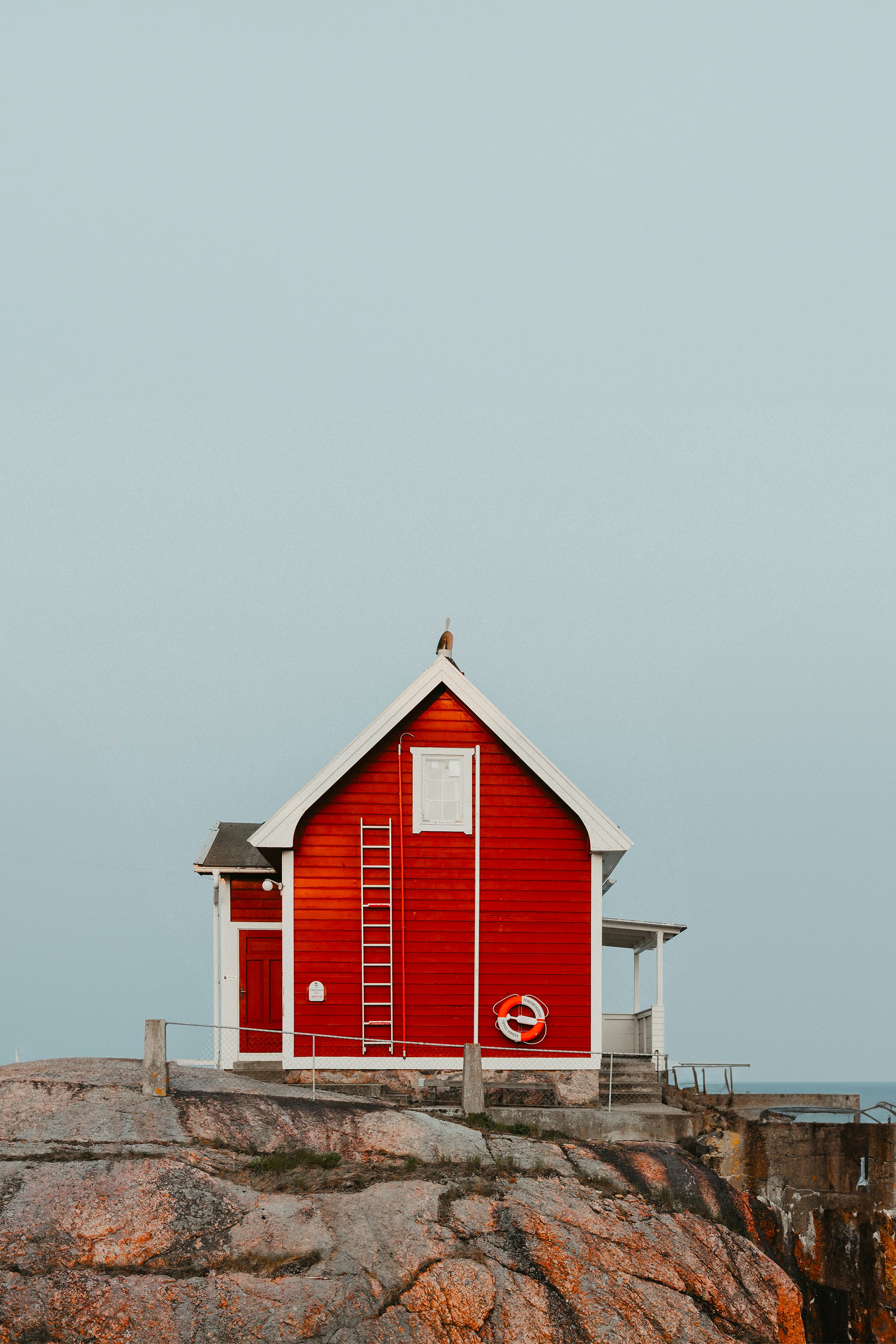 Une maison rouge assise au sommet d’une falaise photo – Photo Rouge ...