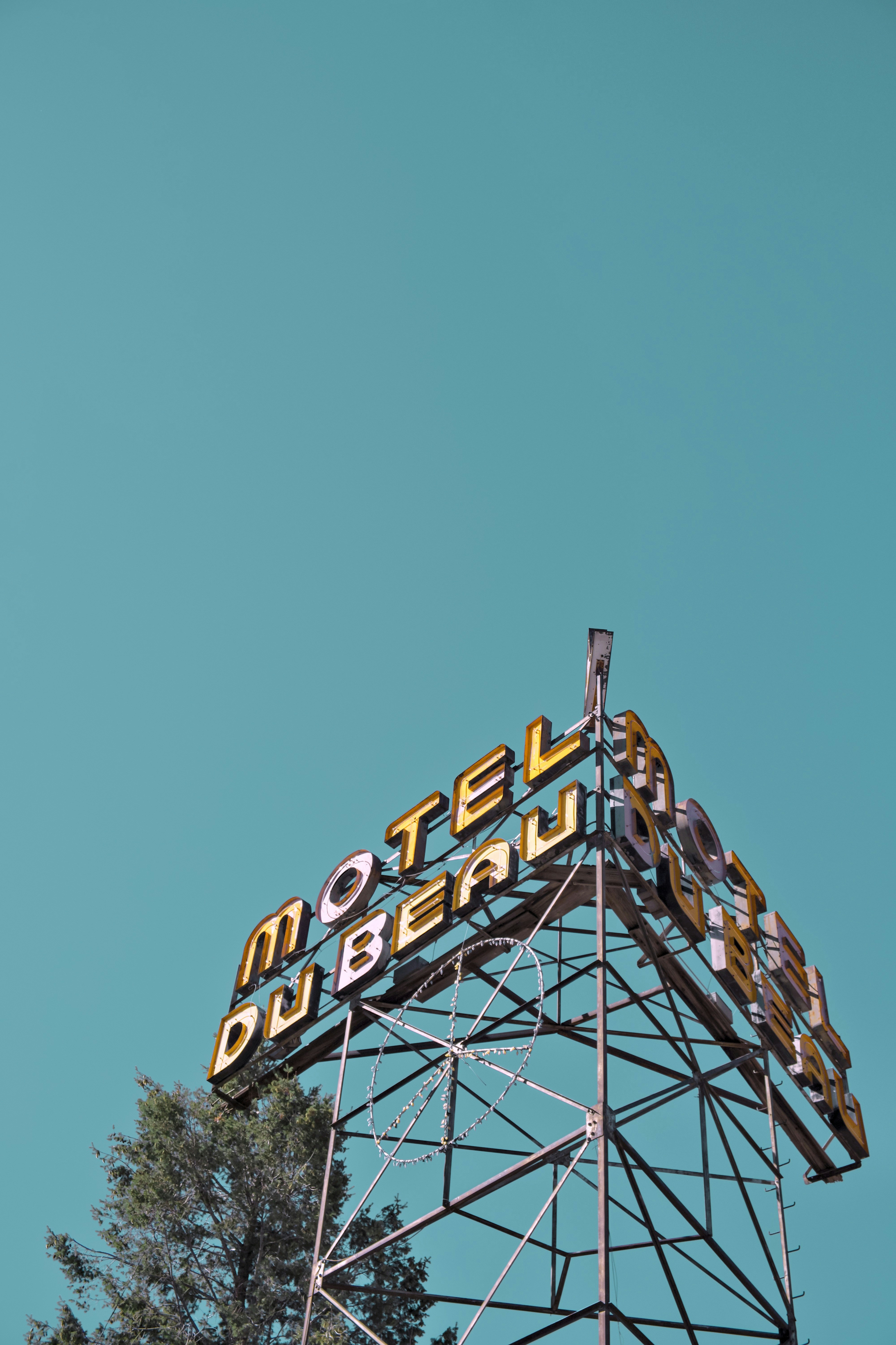 Teal Sky, Golden Letters: Sign Tower Rising Over a Steel Lattice