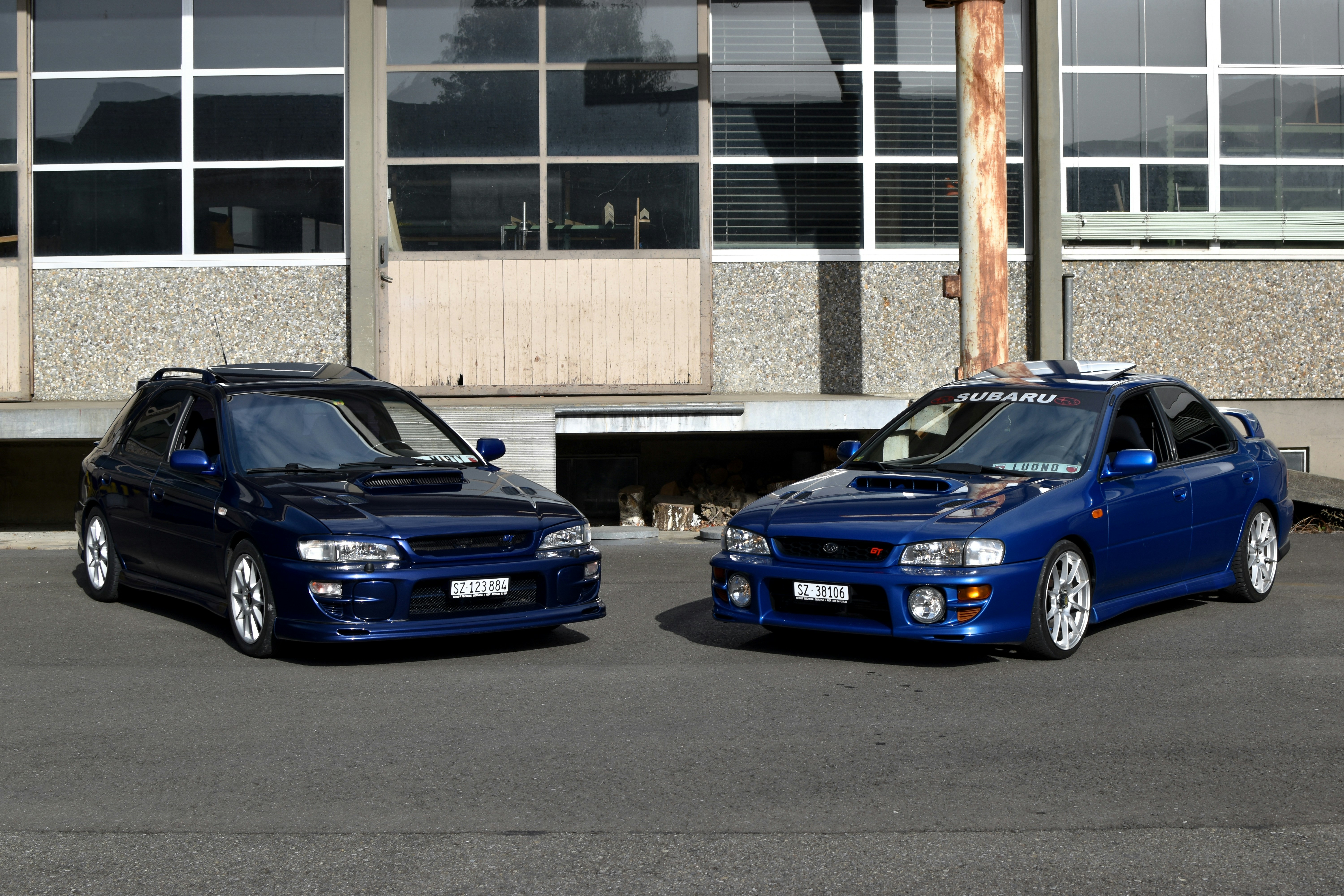 Two blue cars parked next to each other in front of a building photo ...