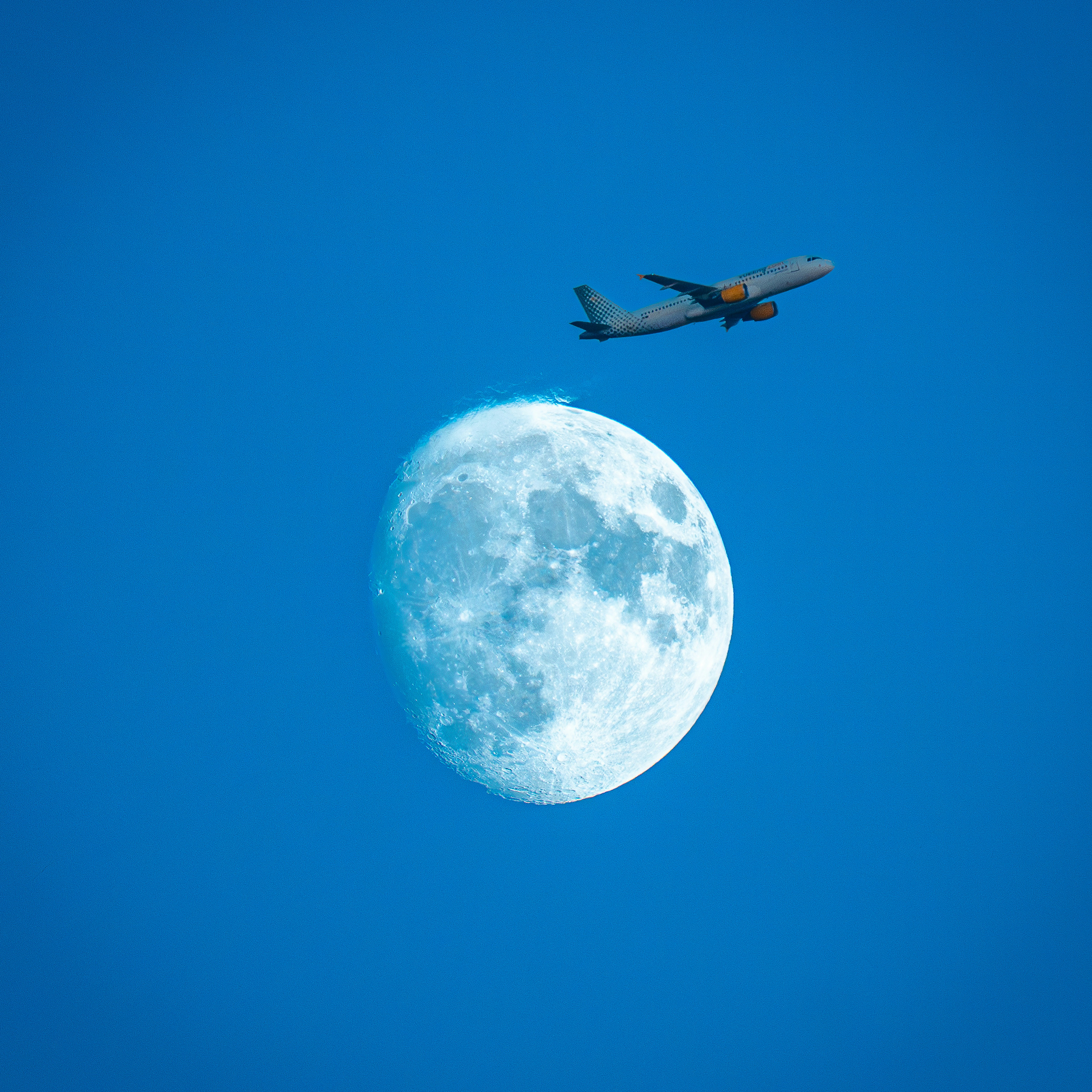 An airplane flying over the moon in a clear blue sky photo – Free Blue ...