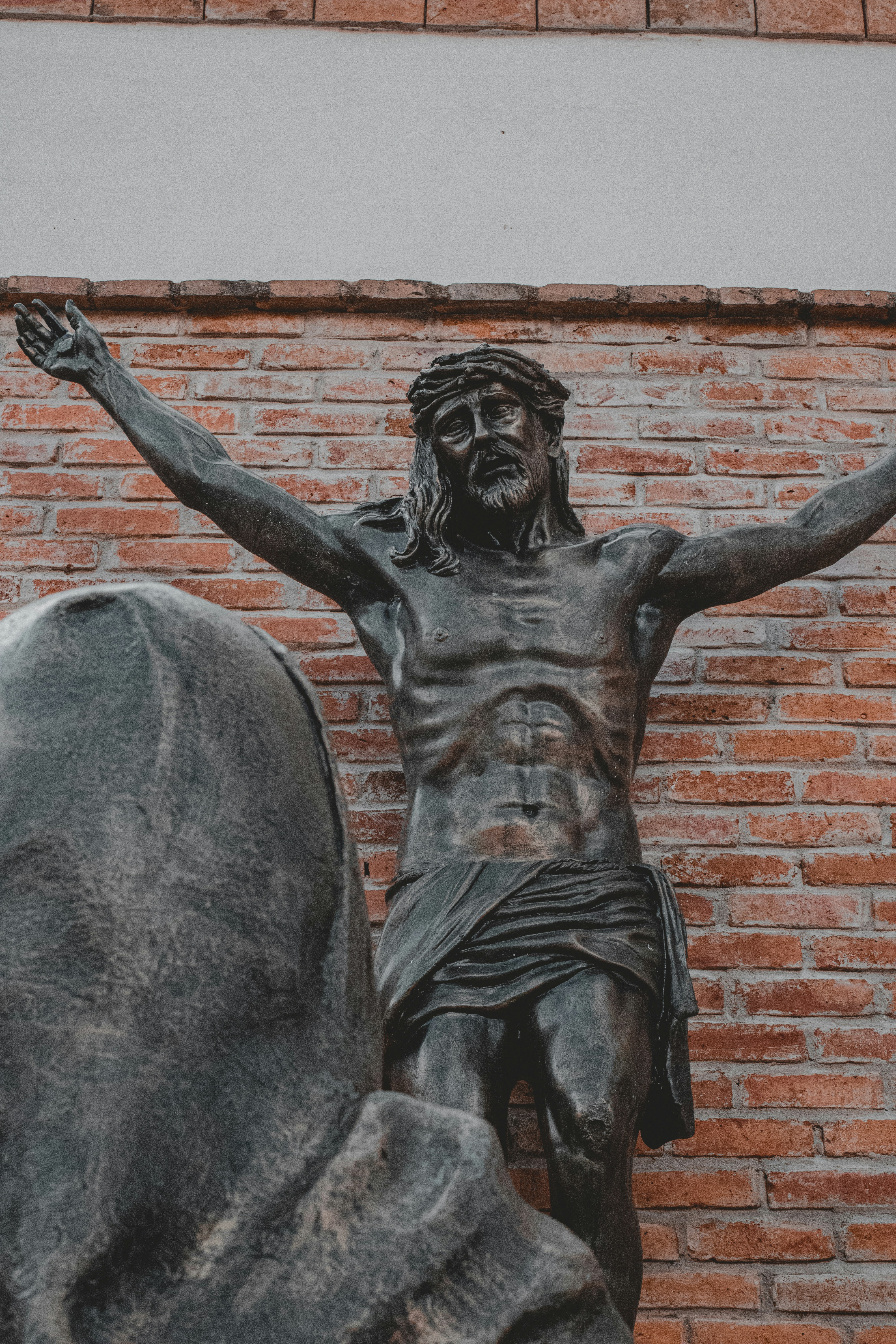 A statue of a man with his hands up in front of a brick wall photo ...