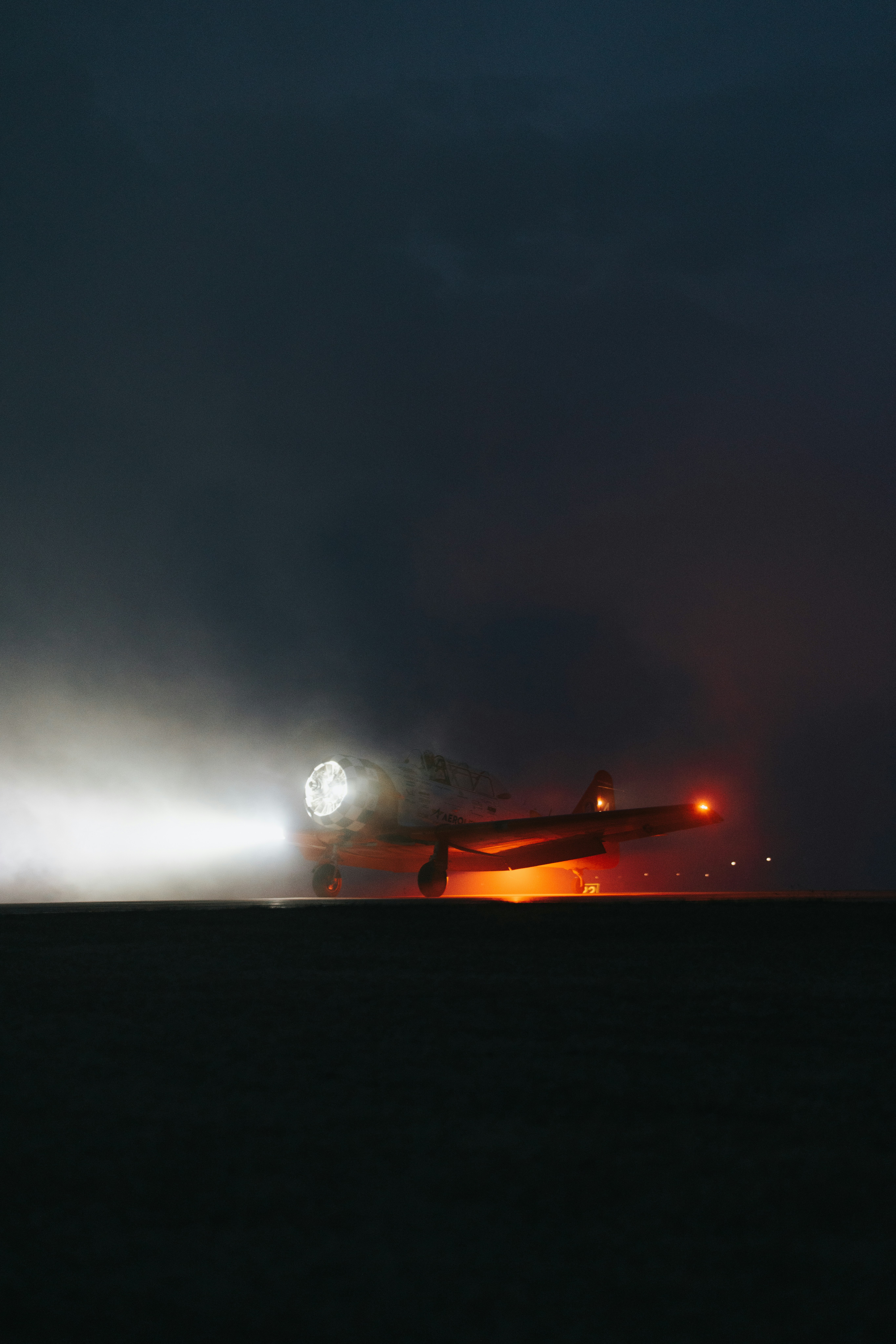 Night Runway Pulse: A Tiny Aircraft Pierces Fog with a Blazing Headlamp