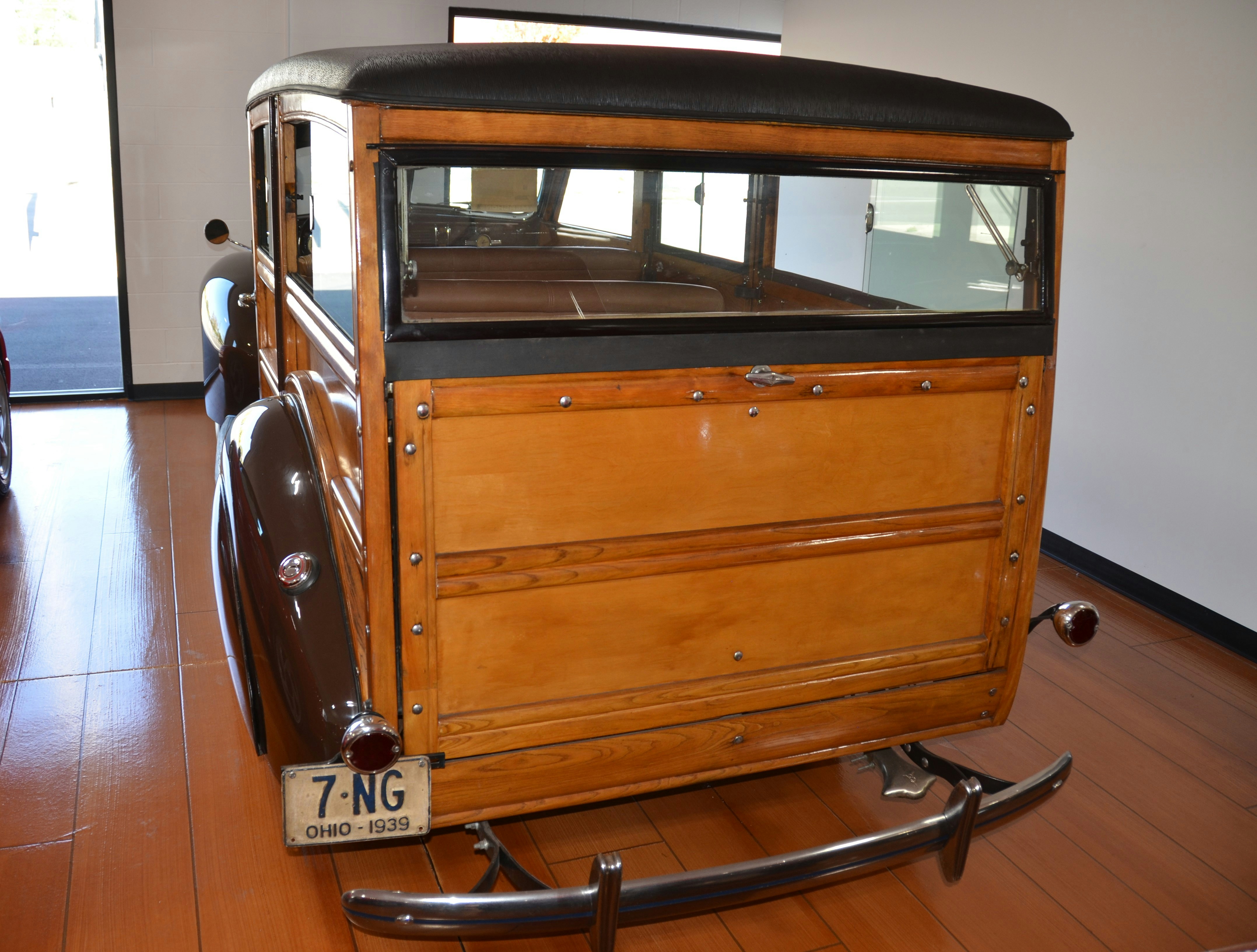 Rear-View Reverie: A 1920s Wooden Sedan in a Sunlit Gallery