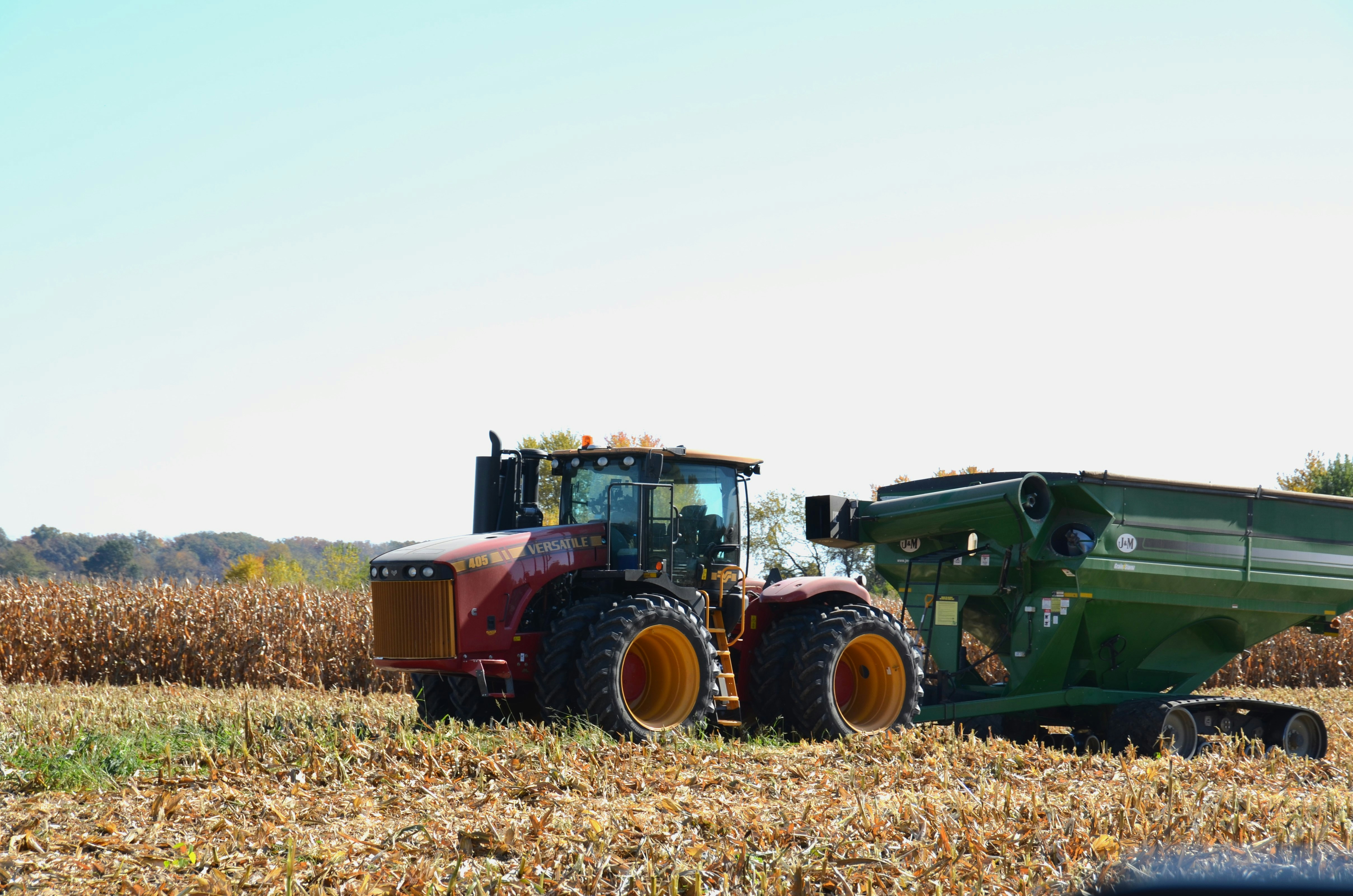 A tractor is driving through a corn field photo – Free Farm Image on ...