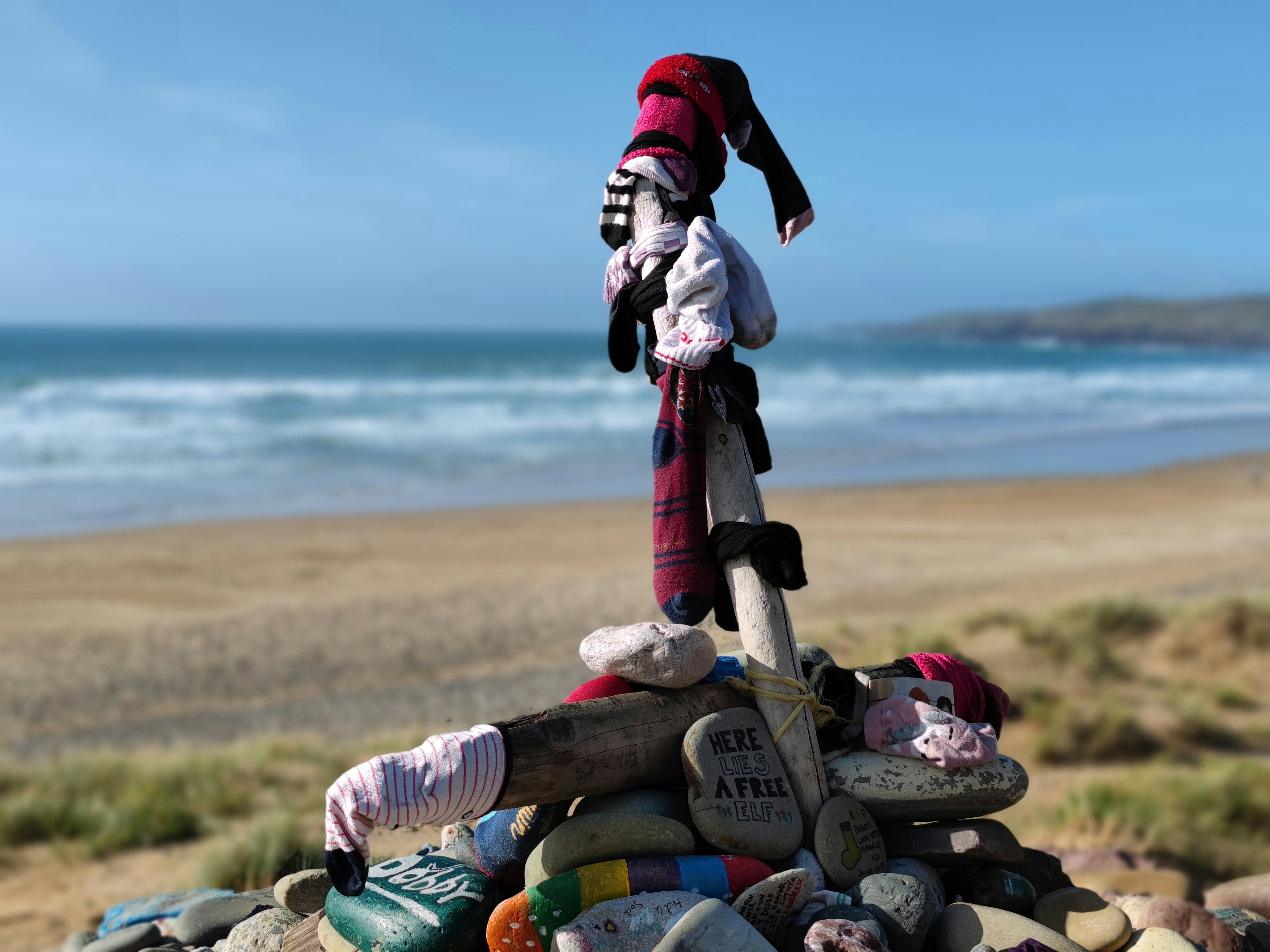Sock Totem Rising from Driftwood: Colorful Beach Sculpture Near the Sea