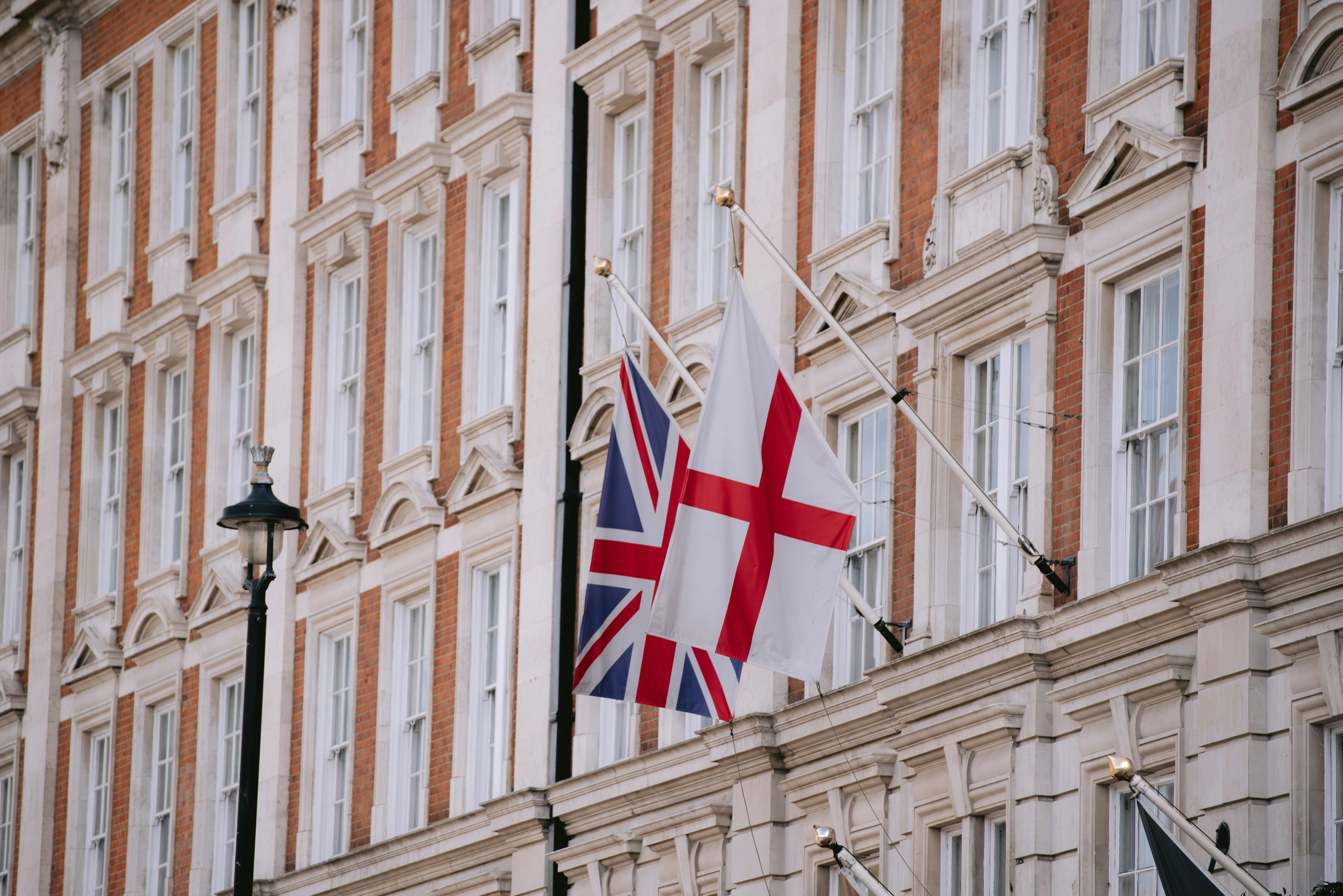Union Jack and St. George's Cross flags fluttering against a backdrop of classic architecture.