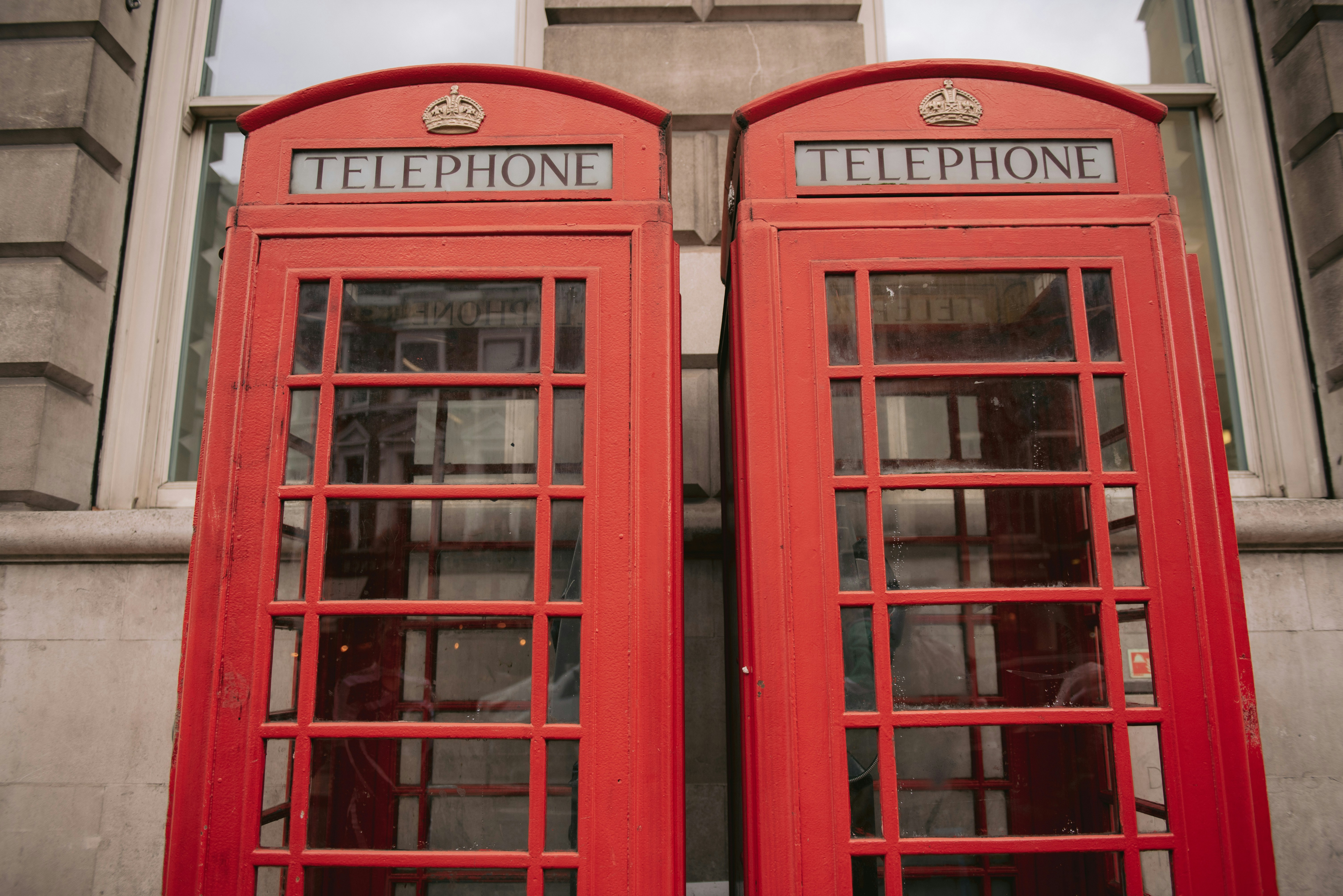 Two red telephone booths in front of a building photo – Free Telephone ...