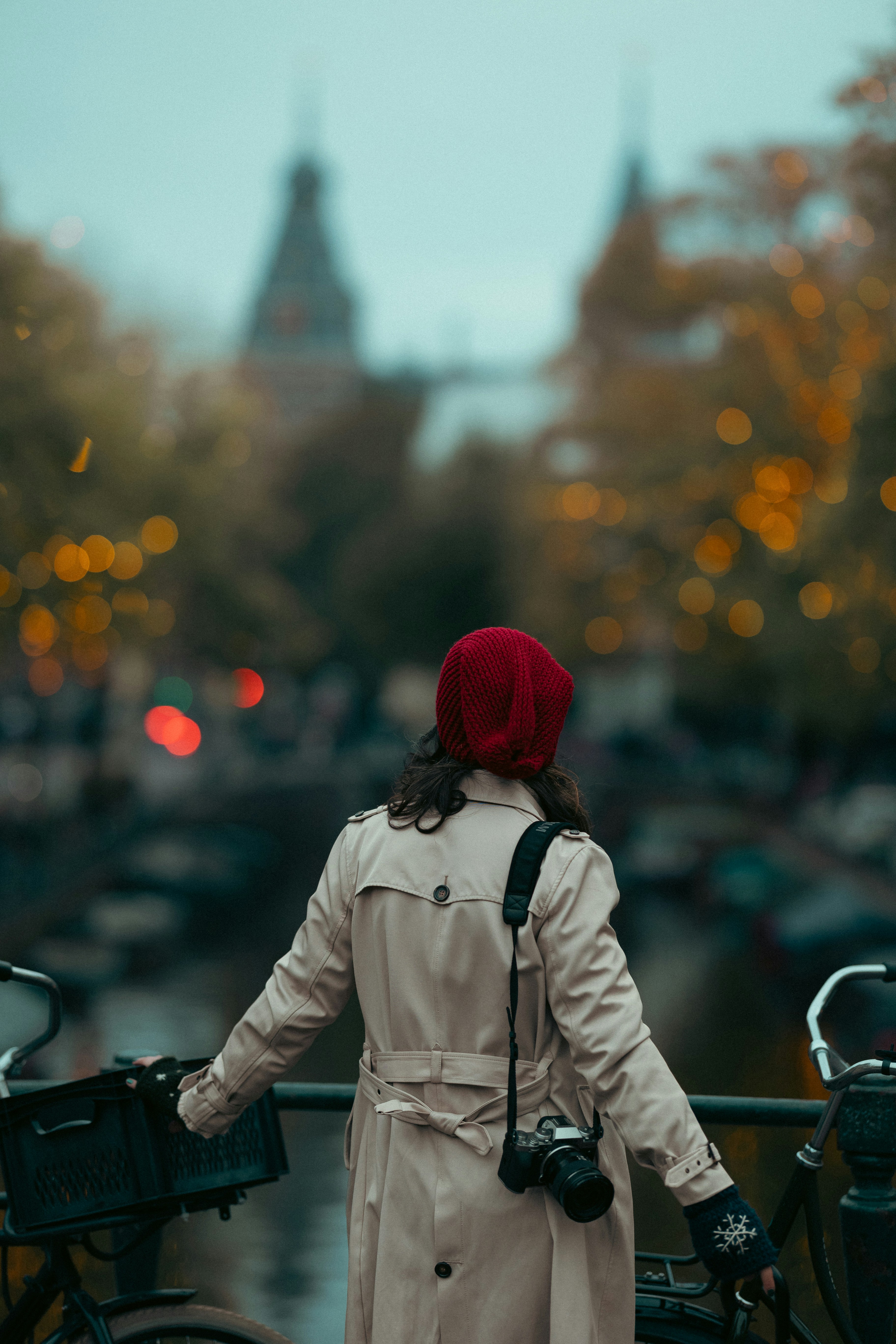 Crimson Beanie Portrait on a Bridge Amid Warm City Lights