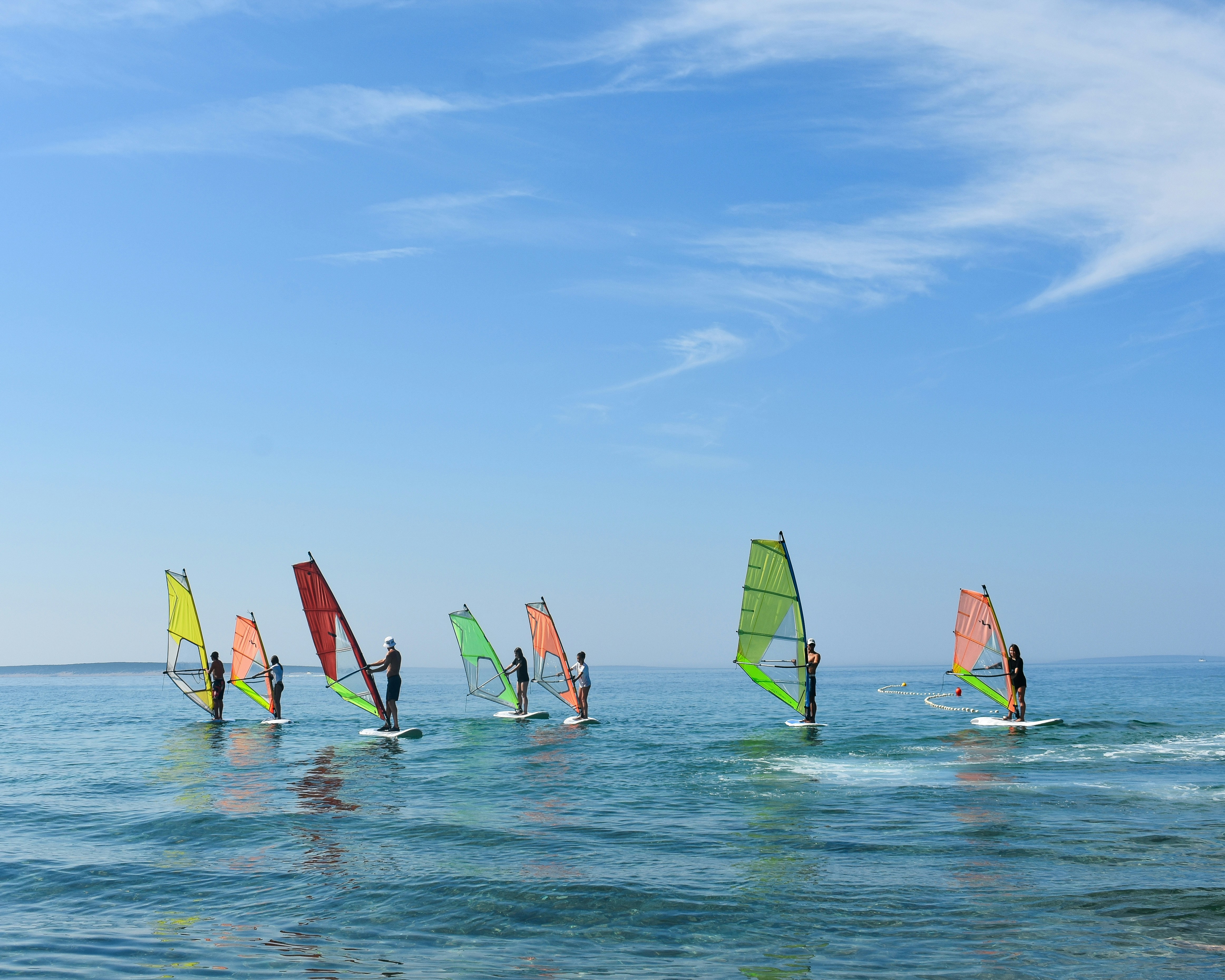 A group of people riding sail boards on top of a body of water photo ...