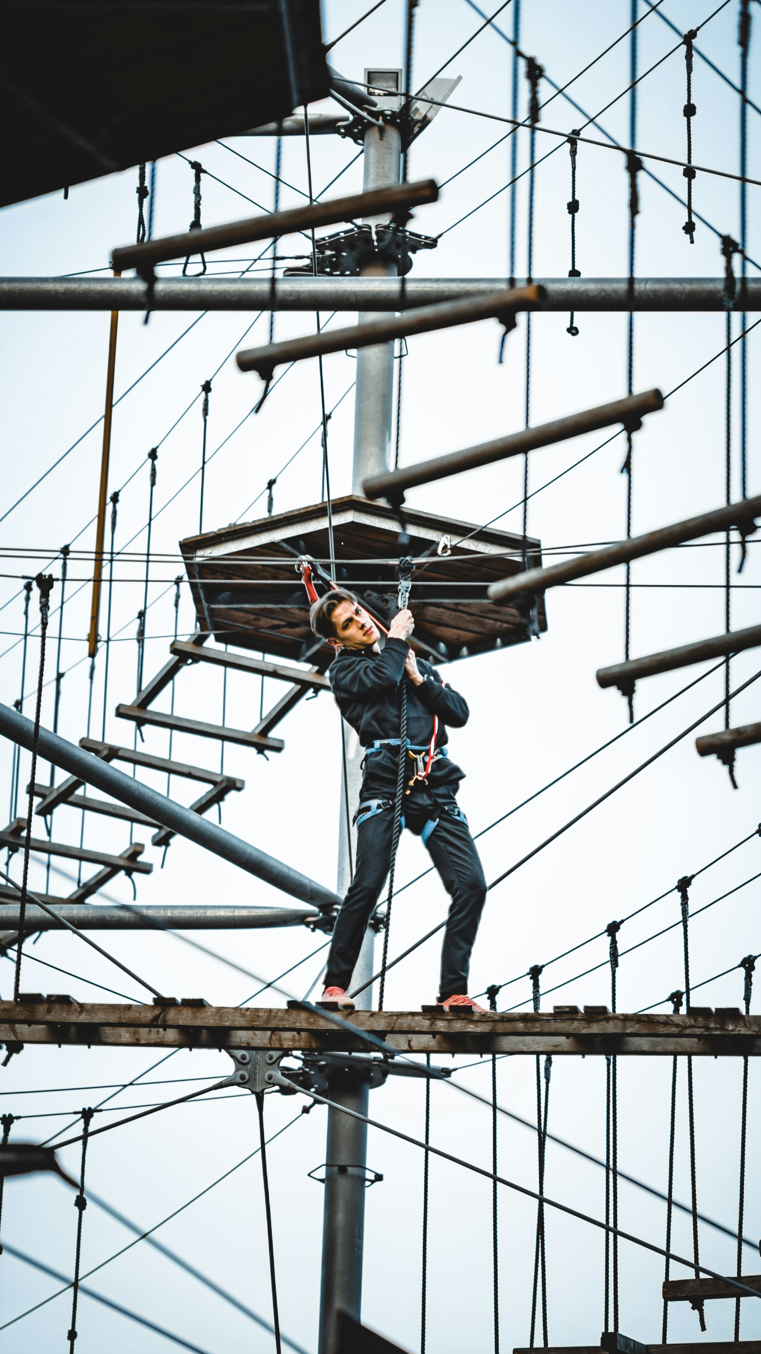 Skyward Threads: A Climber Traverses a Tangle of Ropes and Planks