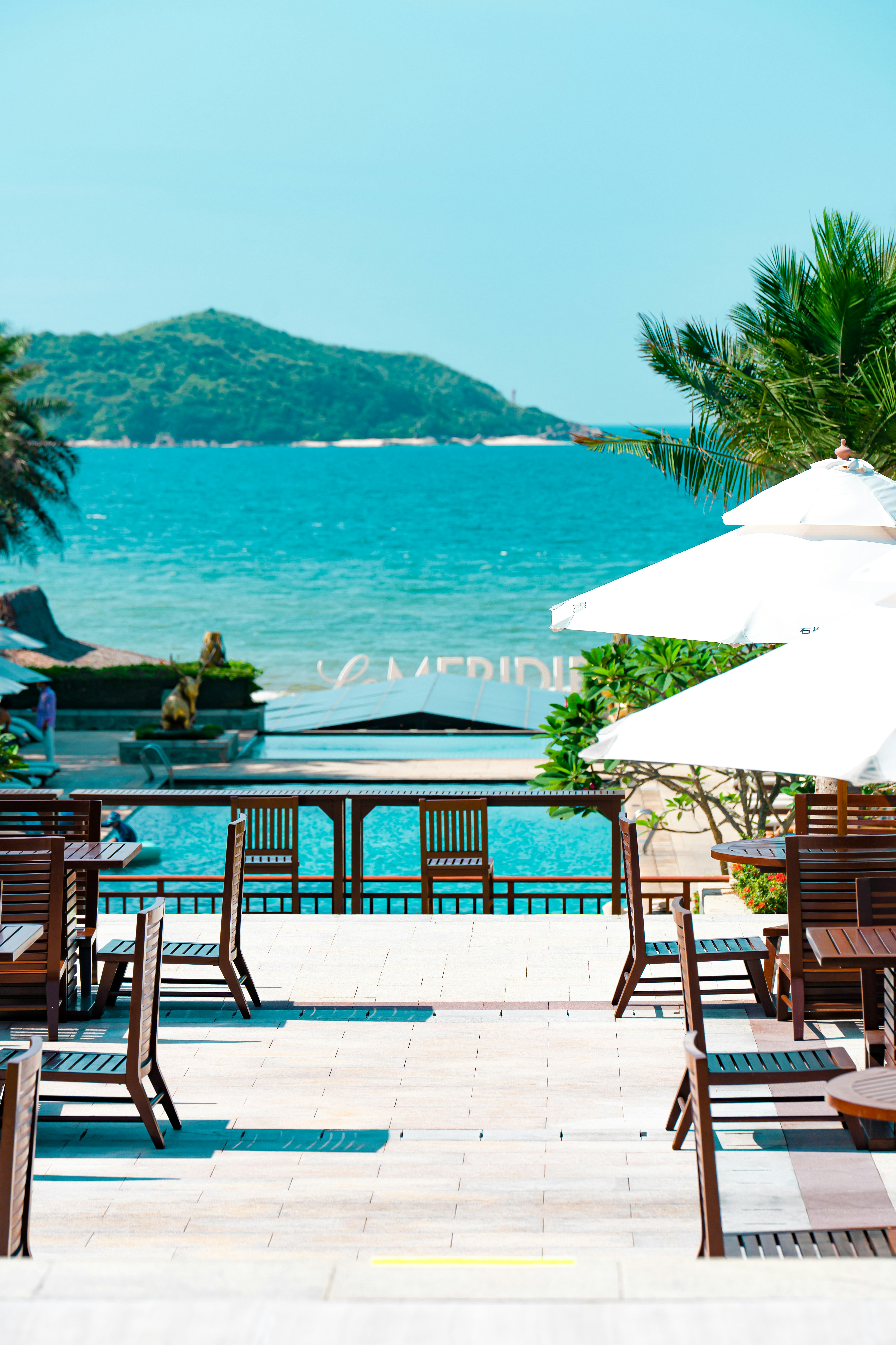 A group of wooden tables sitting under umbrellas photo – Free Beach ...