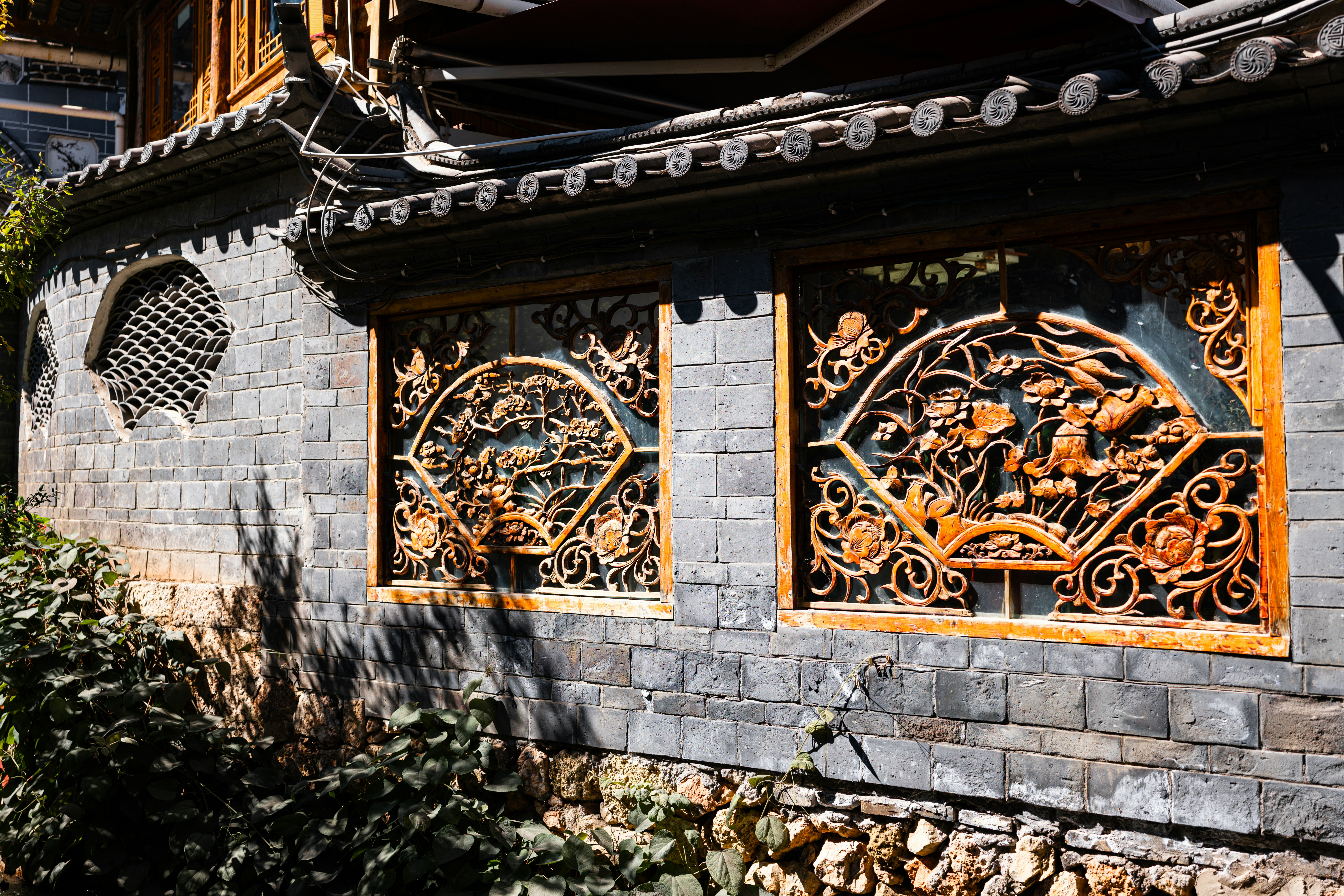 Sunlit Dragon-Carved Lattice Panels Framing a Traditional Stone Wall