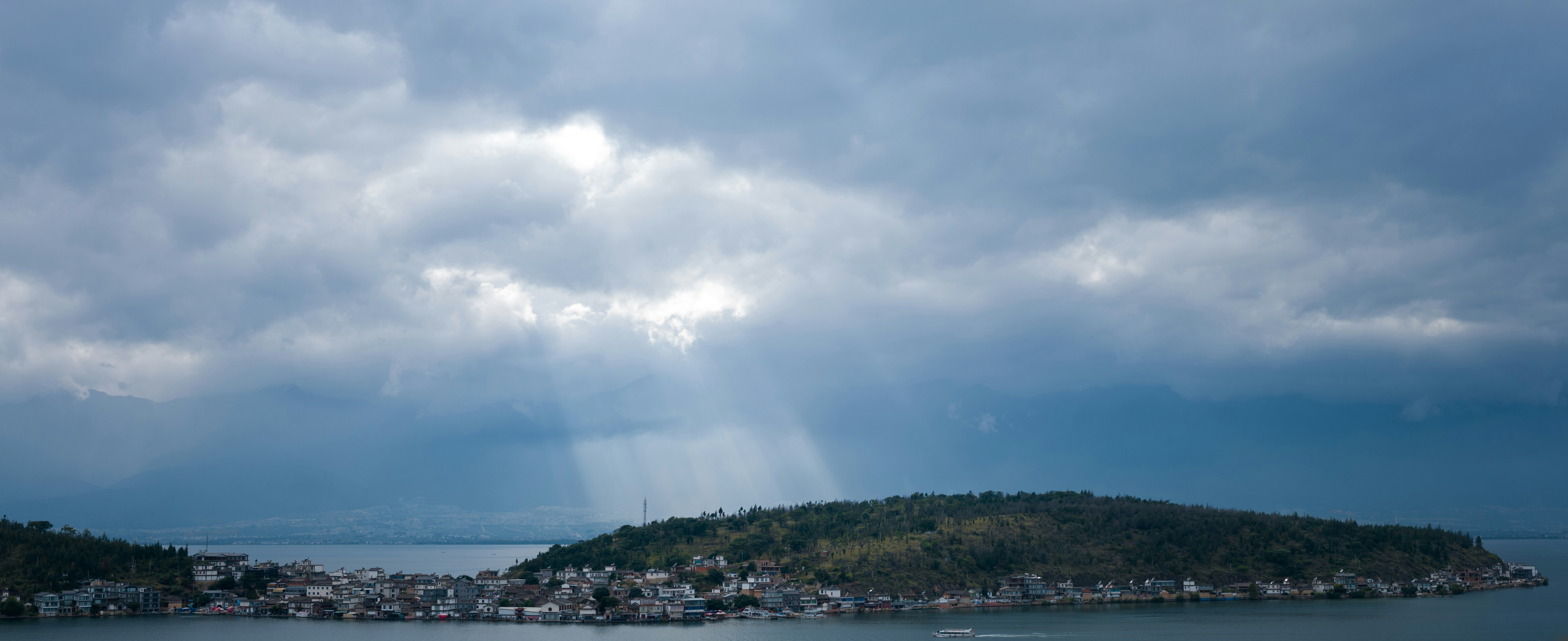 Foto Matahari bersinar menembus awan di atas sebuah pulau kecil ...