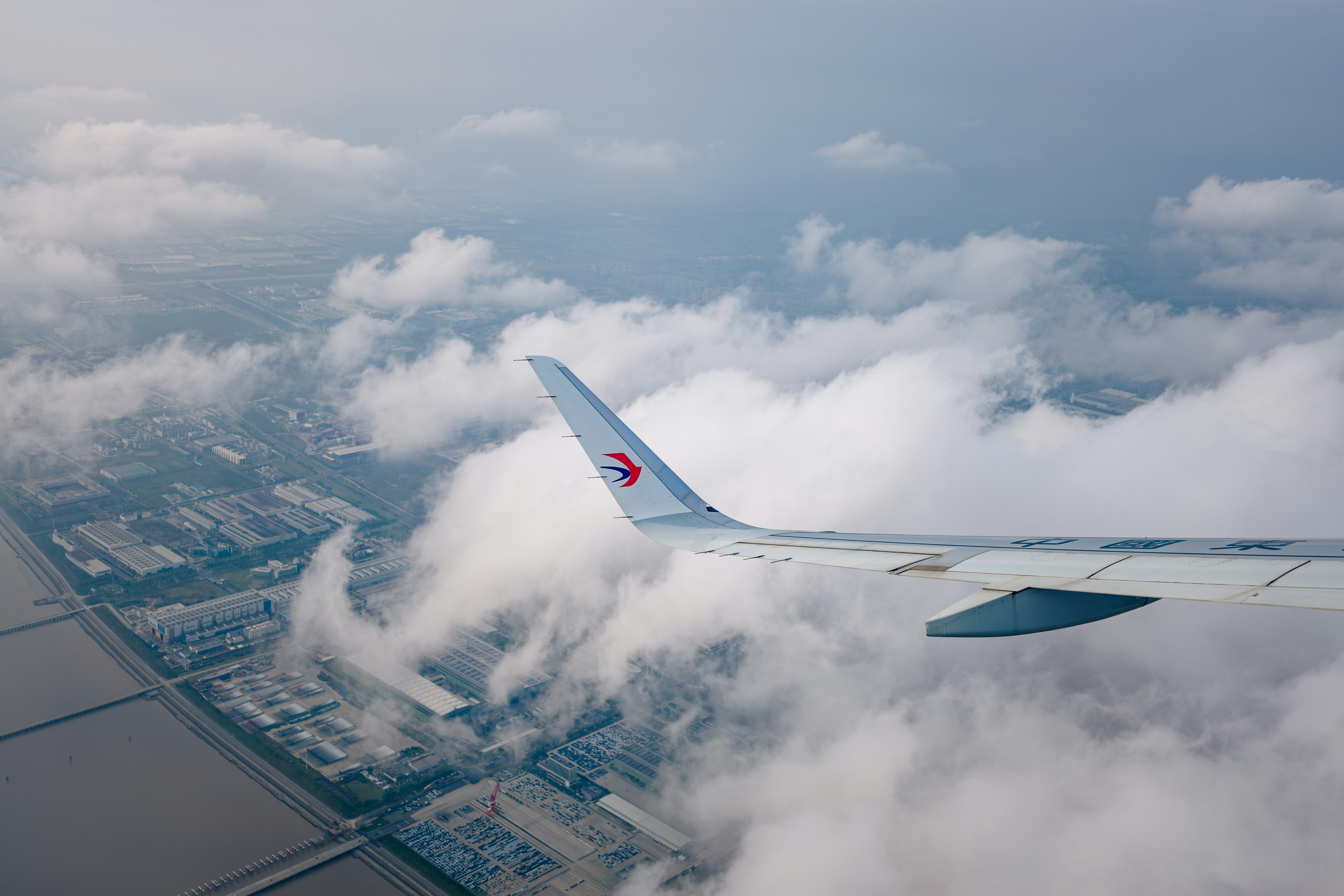 Wingtip Over Clouds: Cloudscape Unfolds Beneath a River City