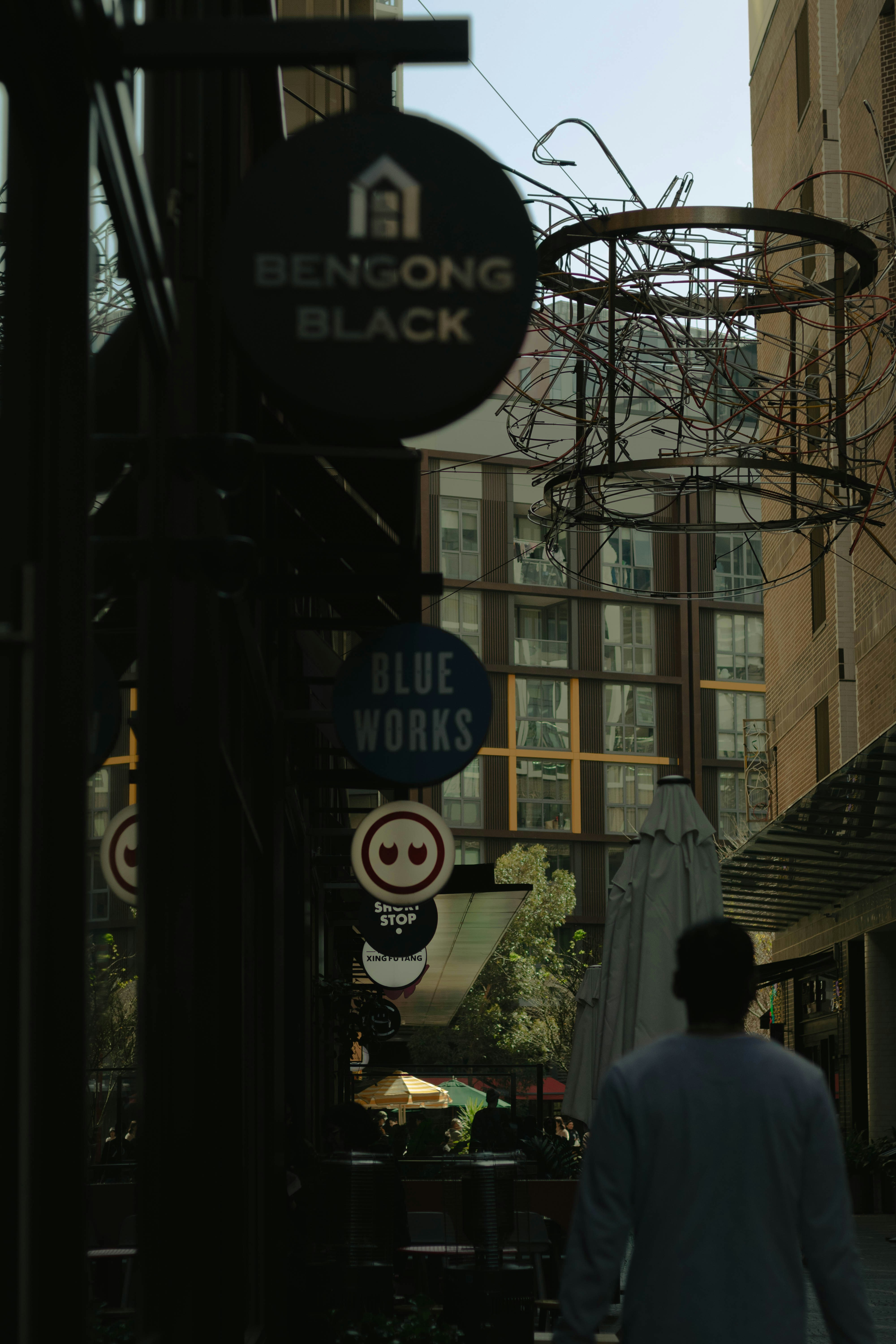 Dusk in the Ringed Alley: A Lone Walk Beneath Circular Metal Orbits