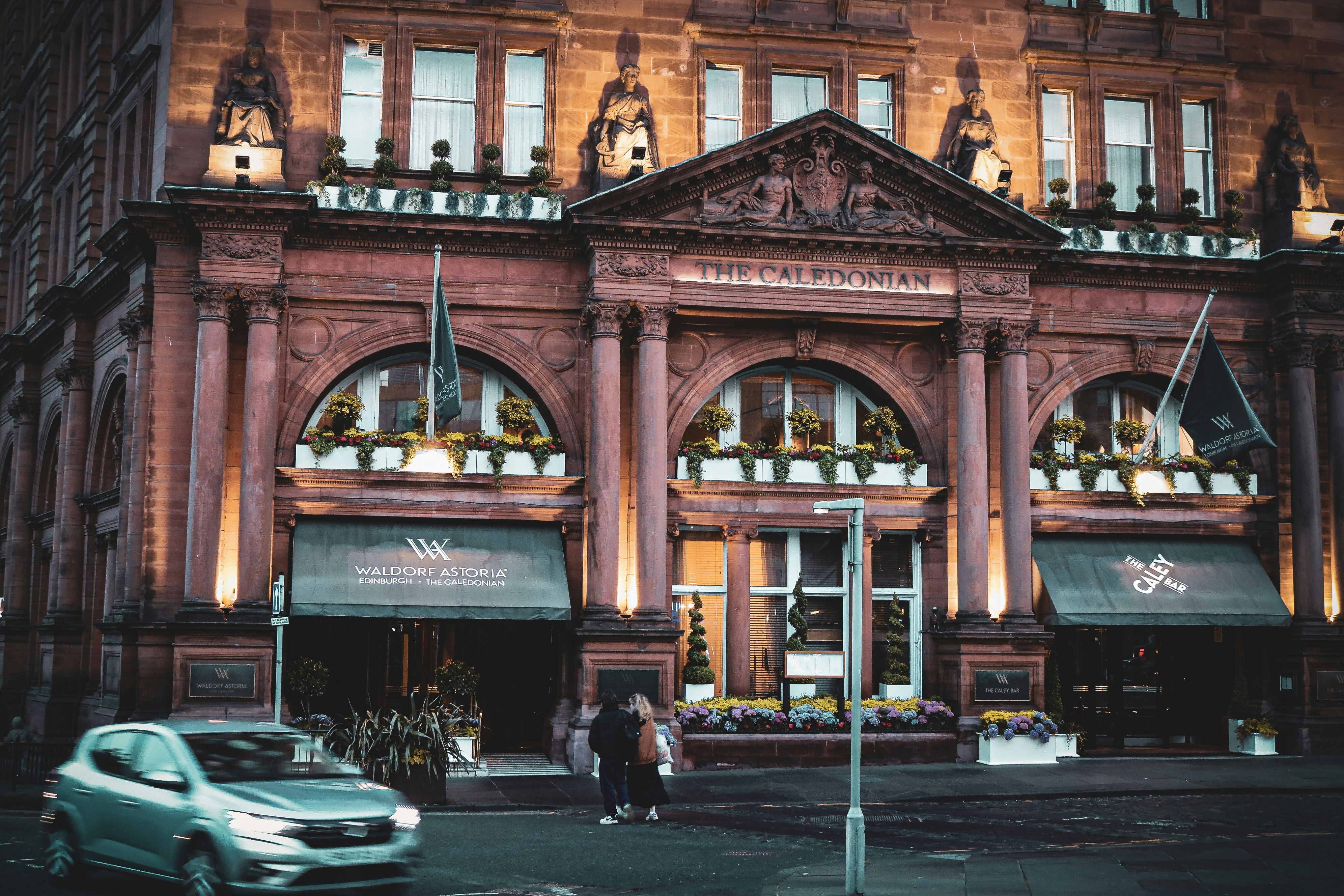 Car parked in front of a historic building with ornate architecture and warm lighting.