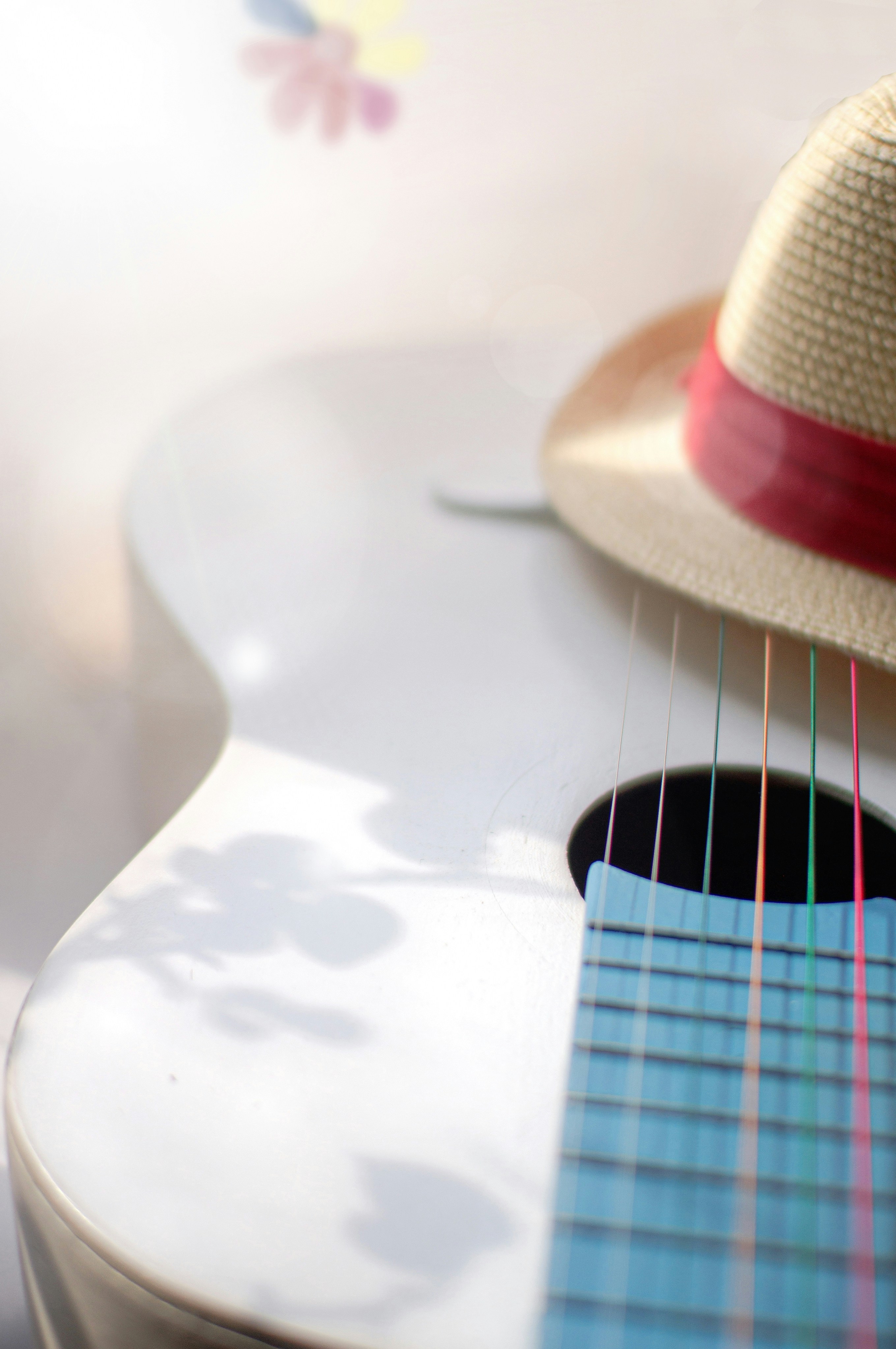 Rainbow Strings Crossing a Sunlit White Guitar Beneath a Straw Hat
