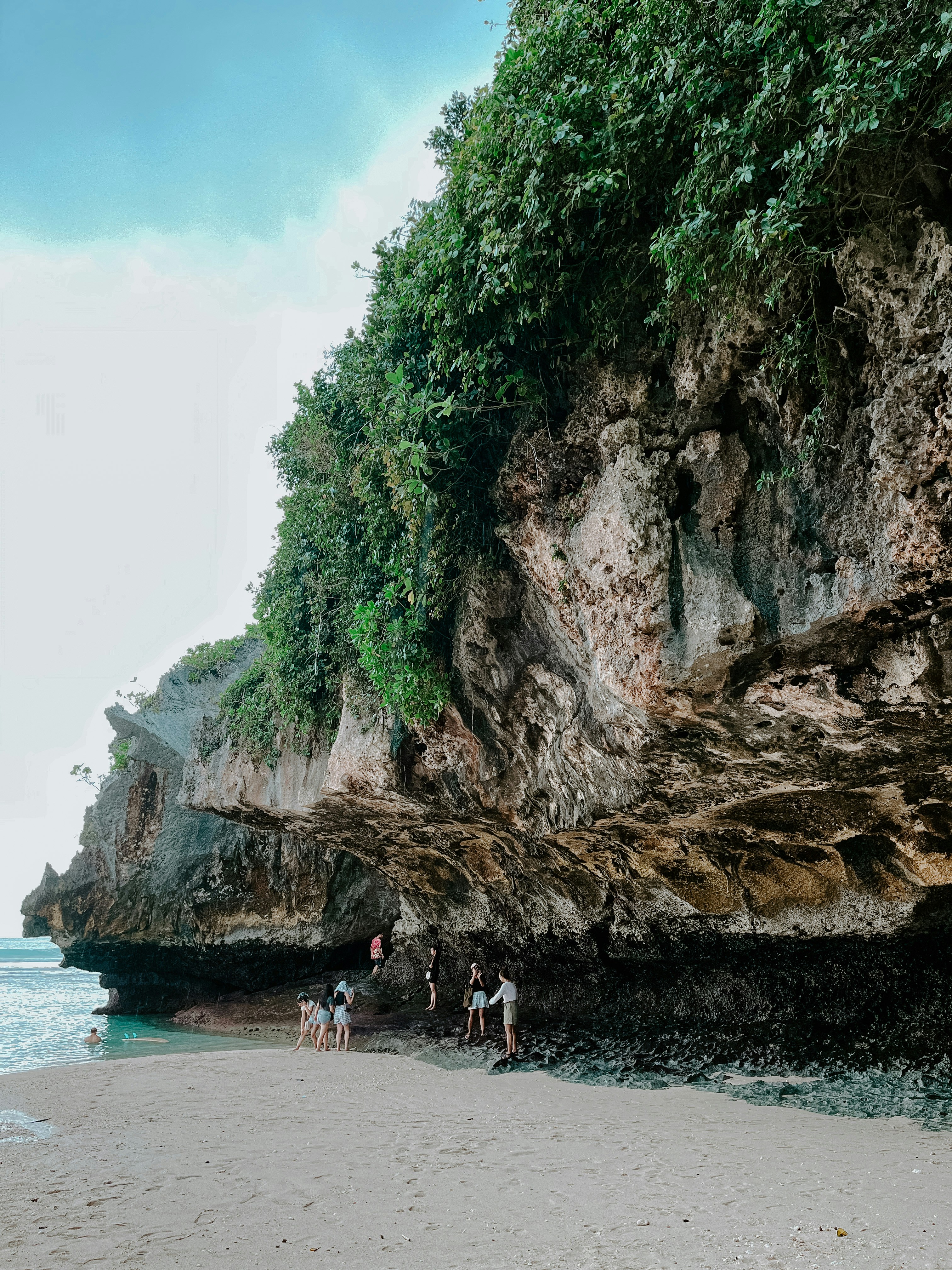 Cliffside Light: A Quiet Beach Gathering Beneath Verdant Overhang