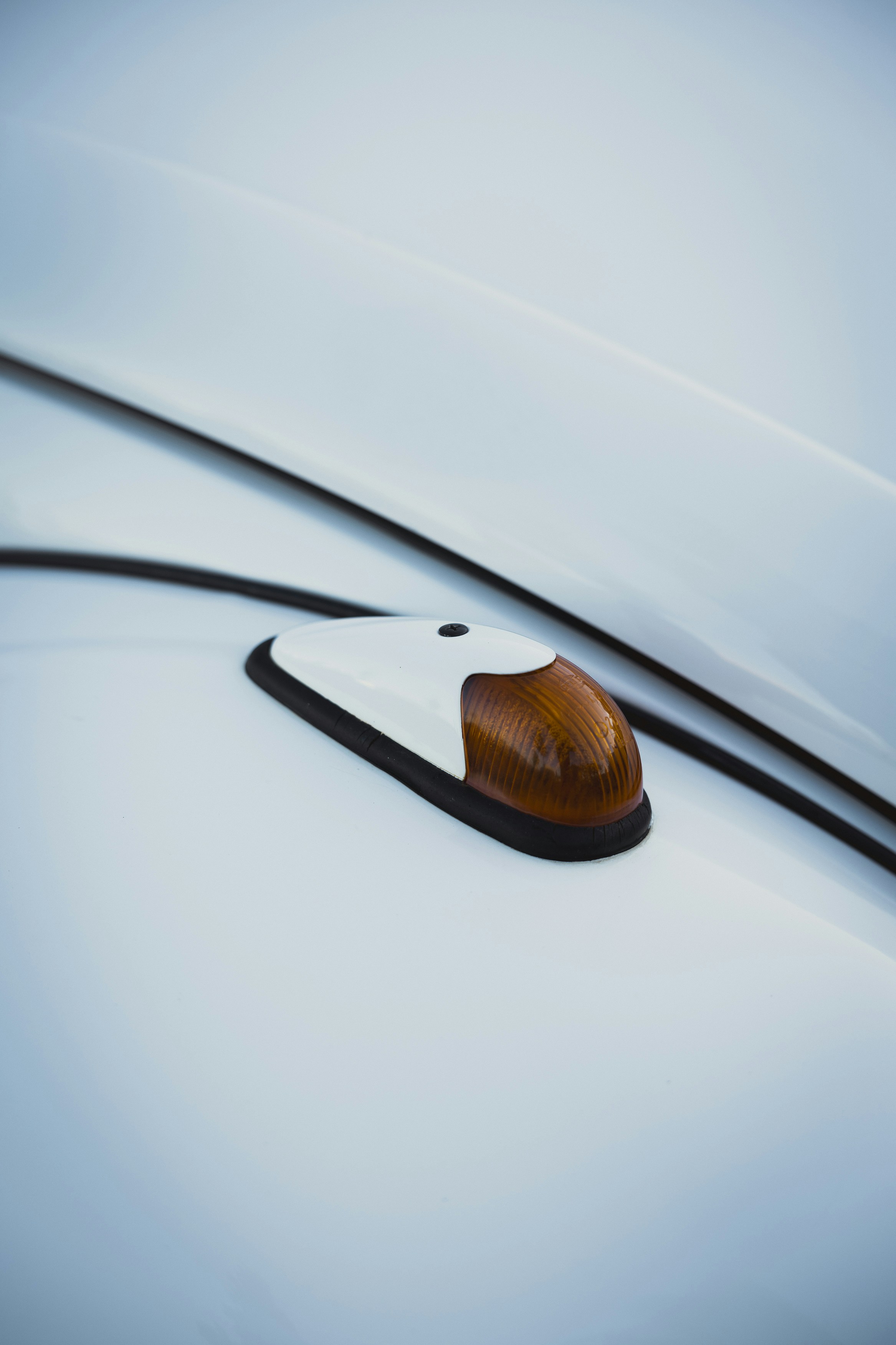 Amber beacon on a curved white hood: a close-up study of automotive geometry
