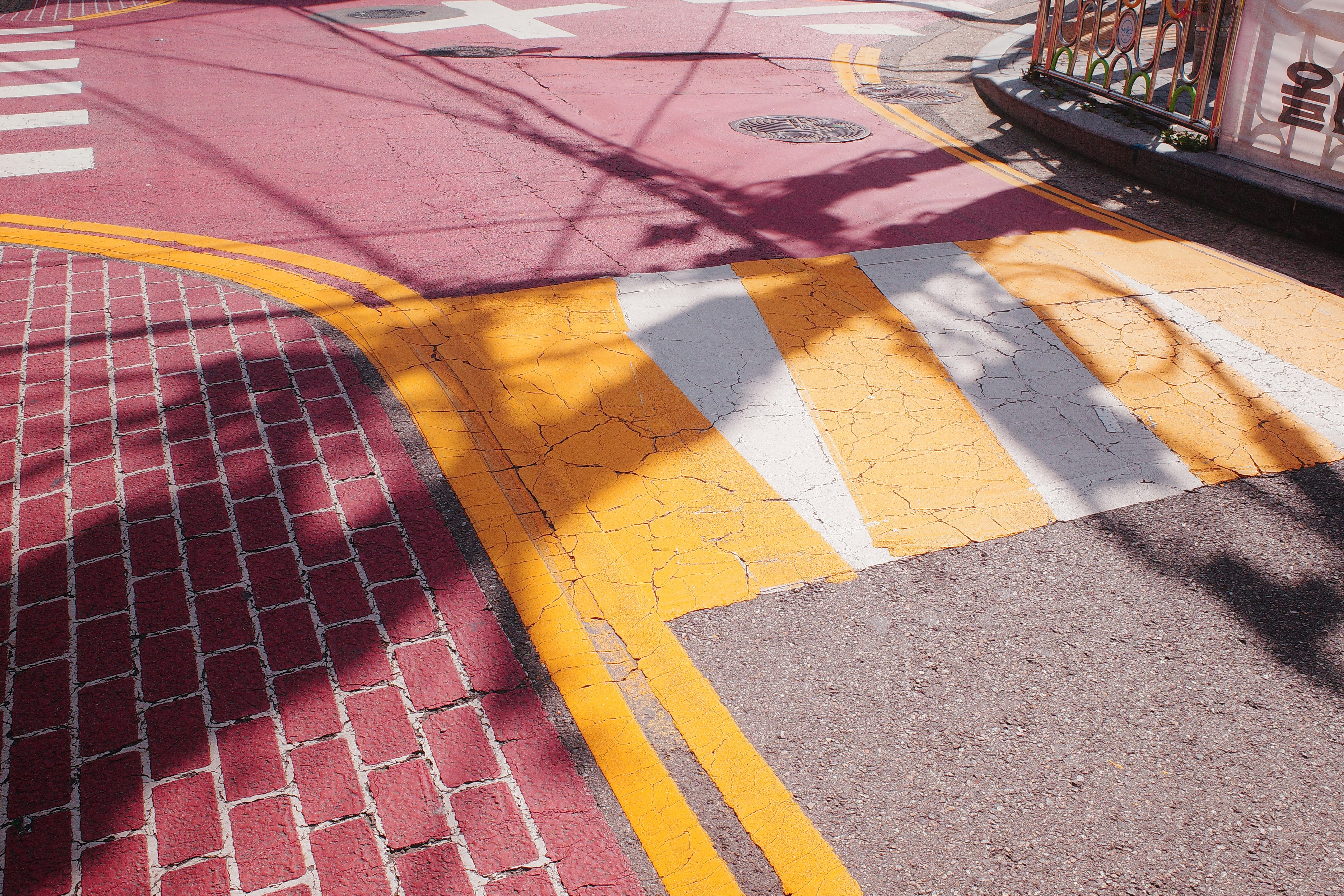 Pink Street Geometry: Yellow Curbs, White Stripes, and Shadowed Lines