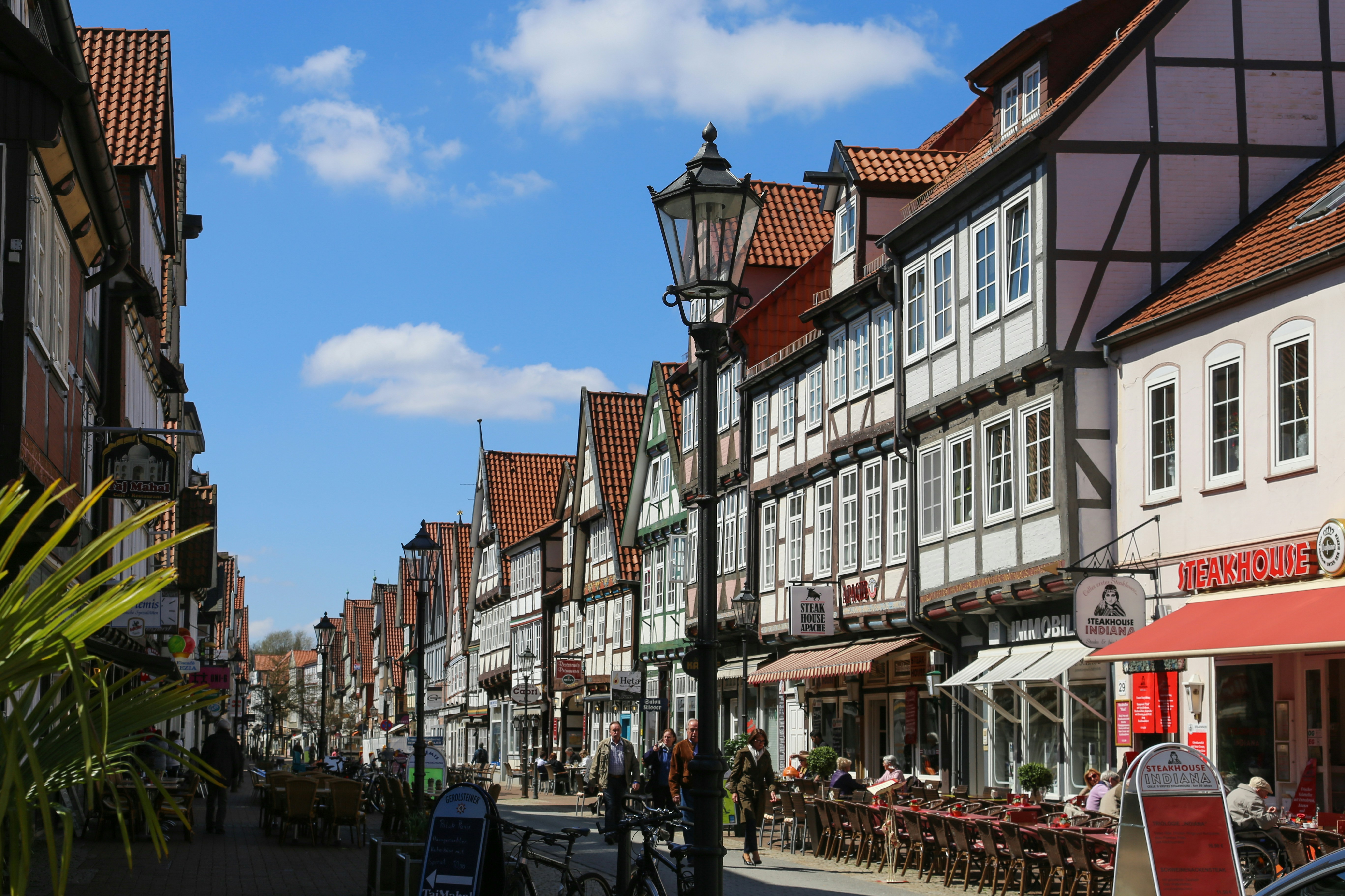 Historic half-timbered buildings line a bustling street under a clear blue sky.