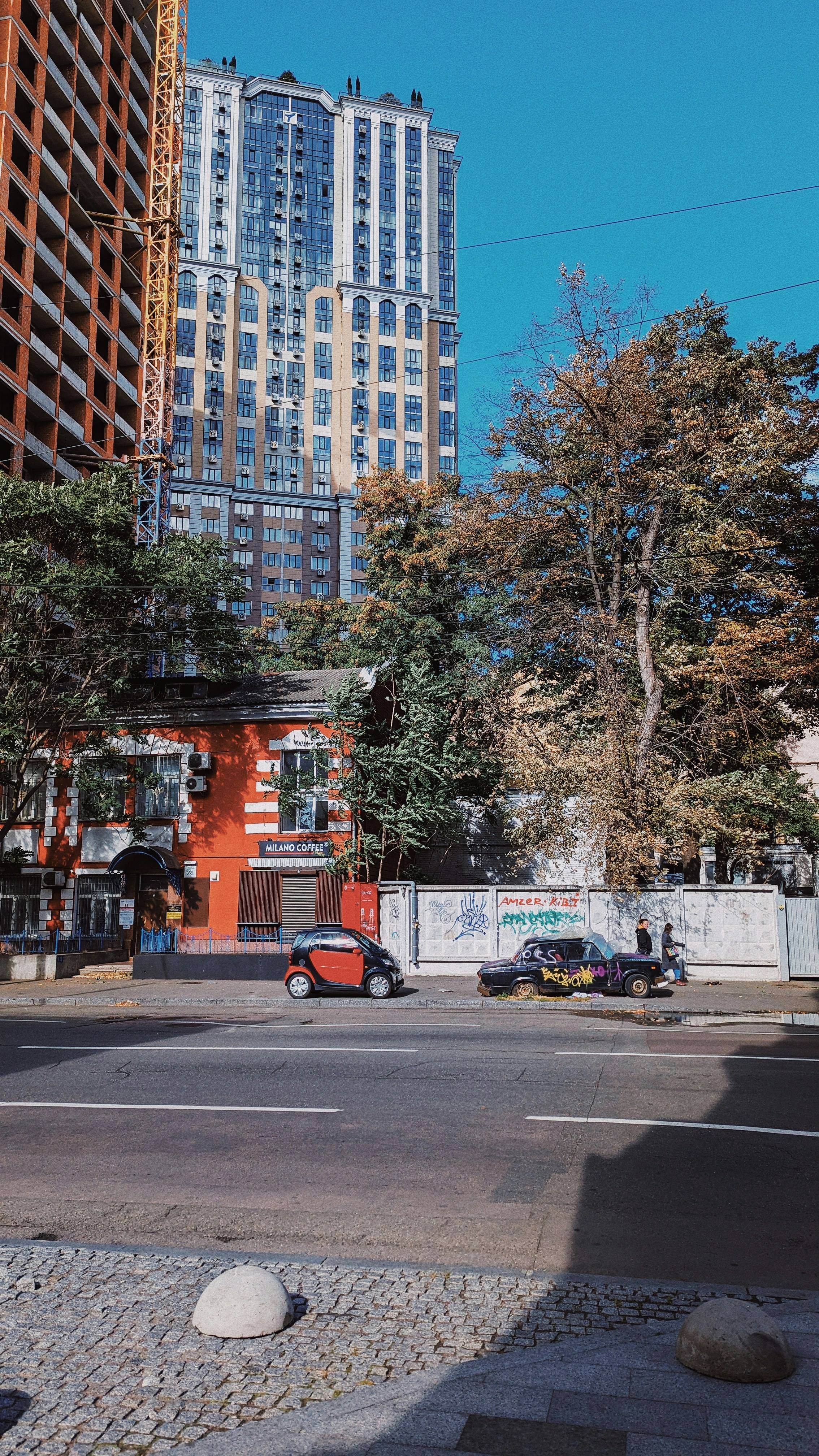 Cobalt Sky Over a Towering Core: Crane, Red Facade, and Street Pulse