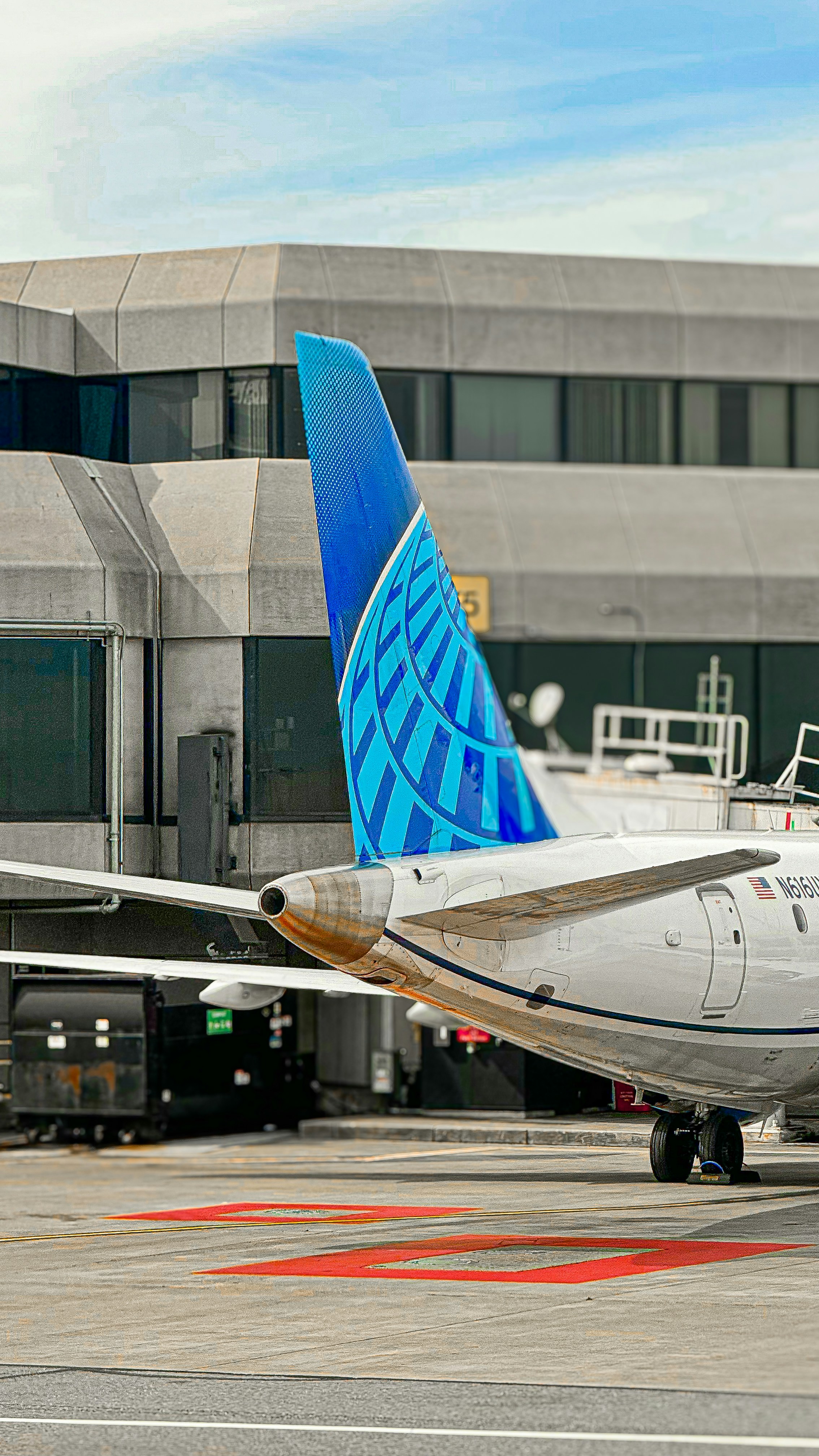 Vibrant blue airline tail against a modern airport backdrop, showcasing sleek design and engineering. The composition highlights the intersection of technology and travel.