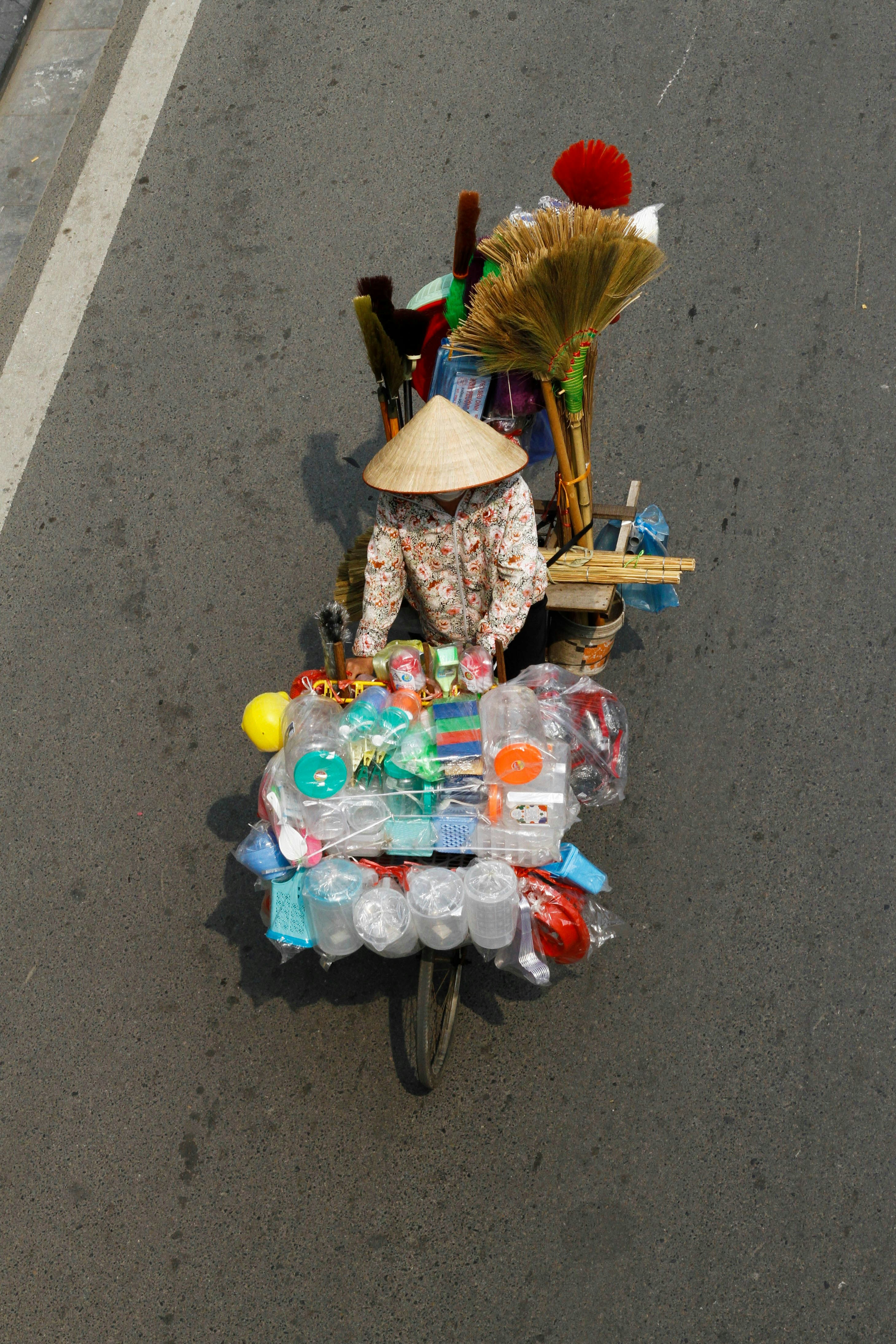 Aerial Street Vendor: Conical-Hat Courier Brimming with Colorful Goods