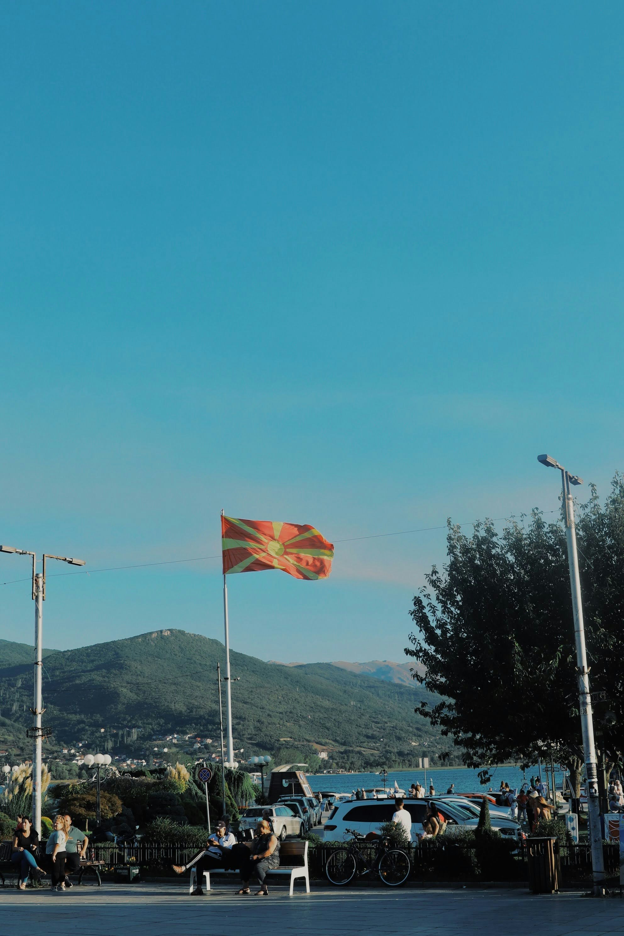A group of people sitting on a bench under a flag photo – Free Car ...