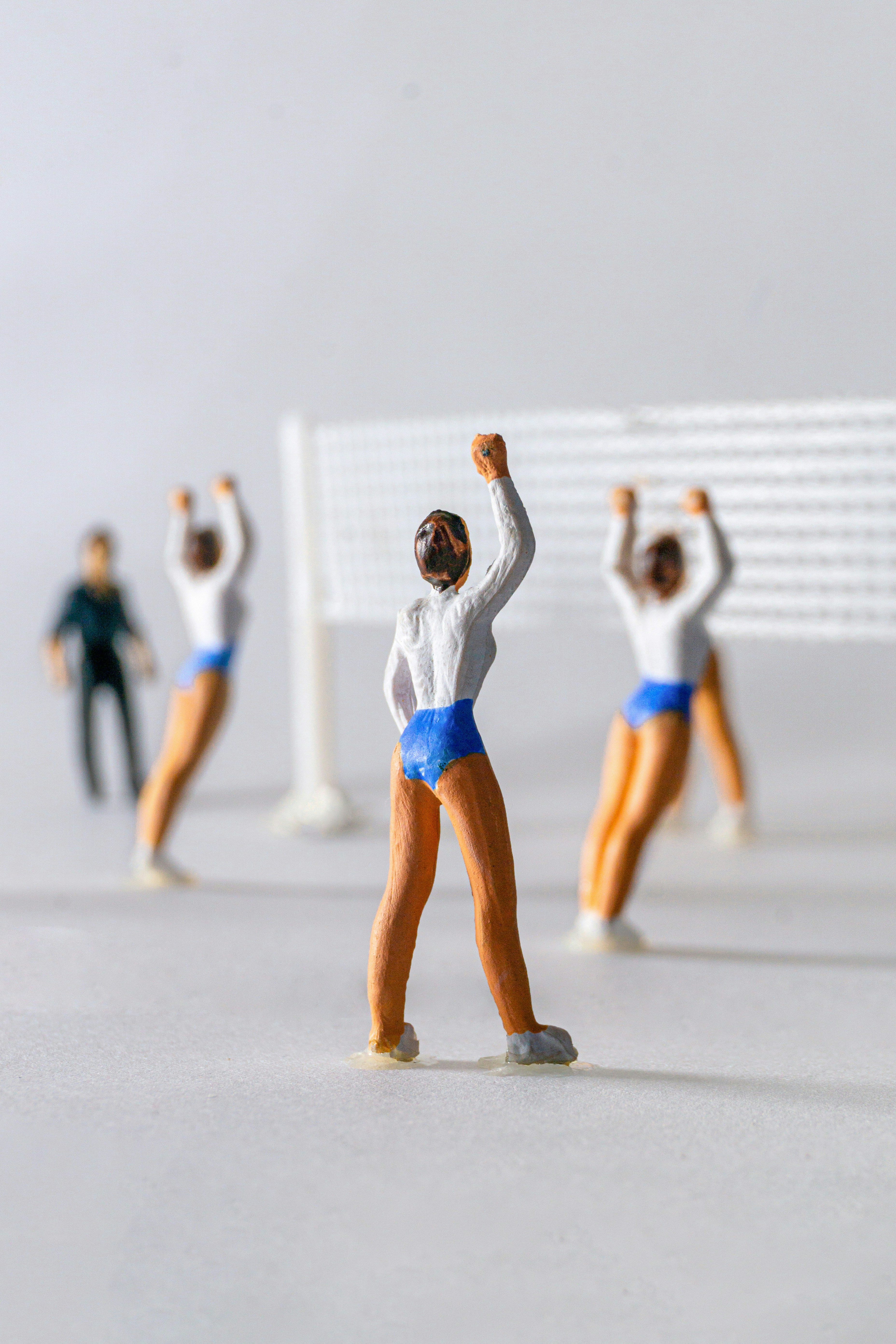 A group of miniature figurines of people playing a game of volleyball ...