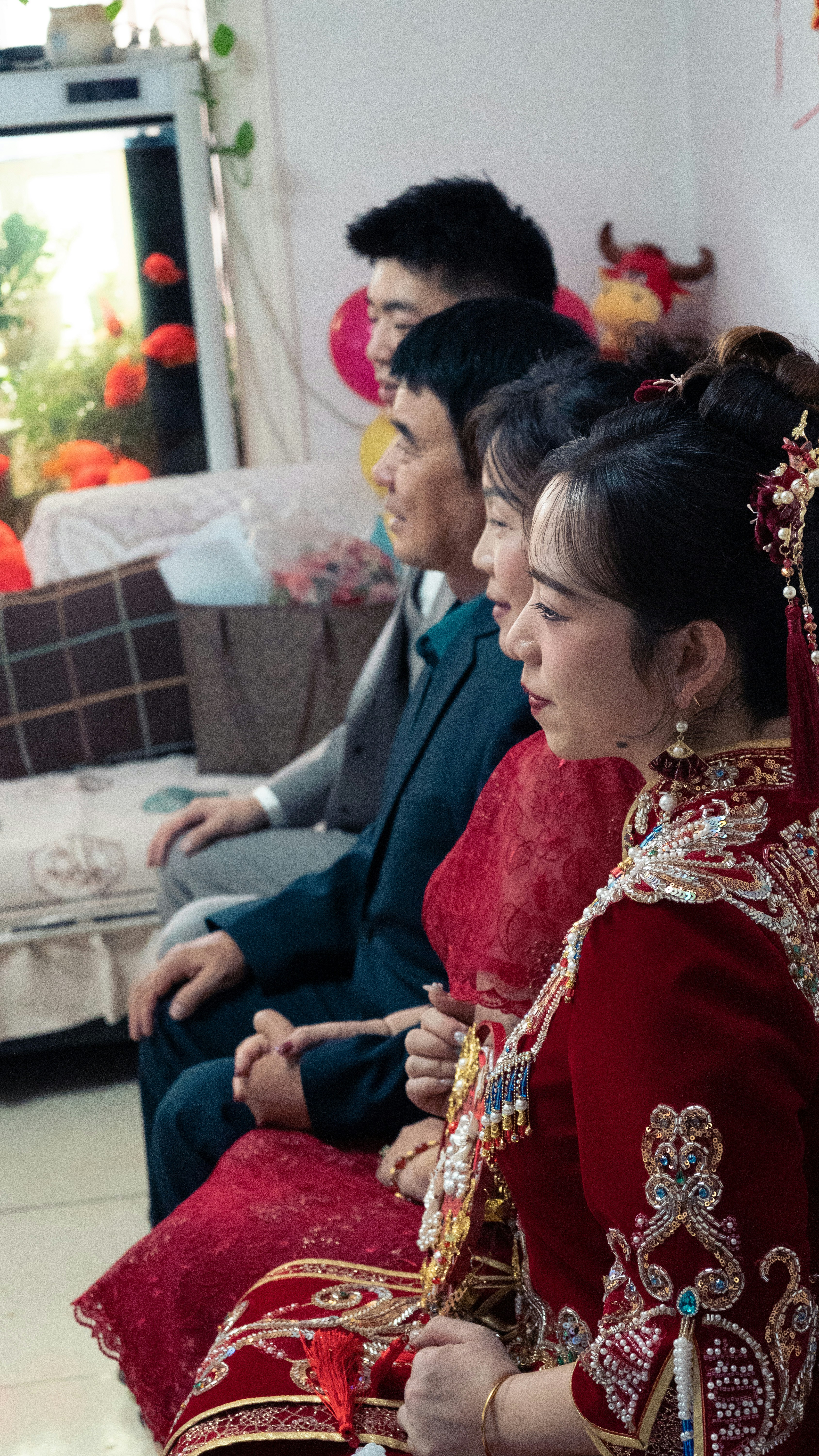 Bride in ornate red dress in profile during a ceremonial gathering