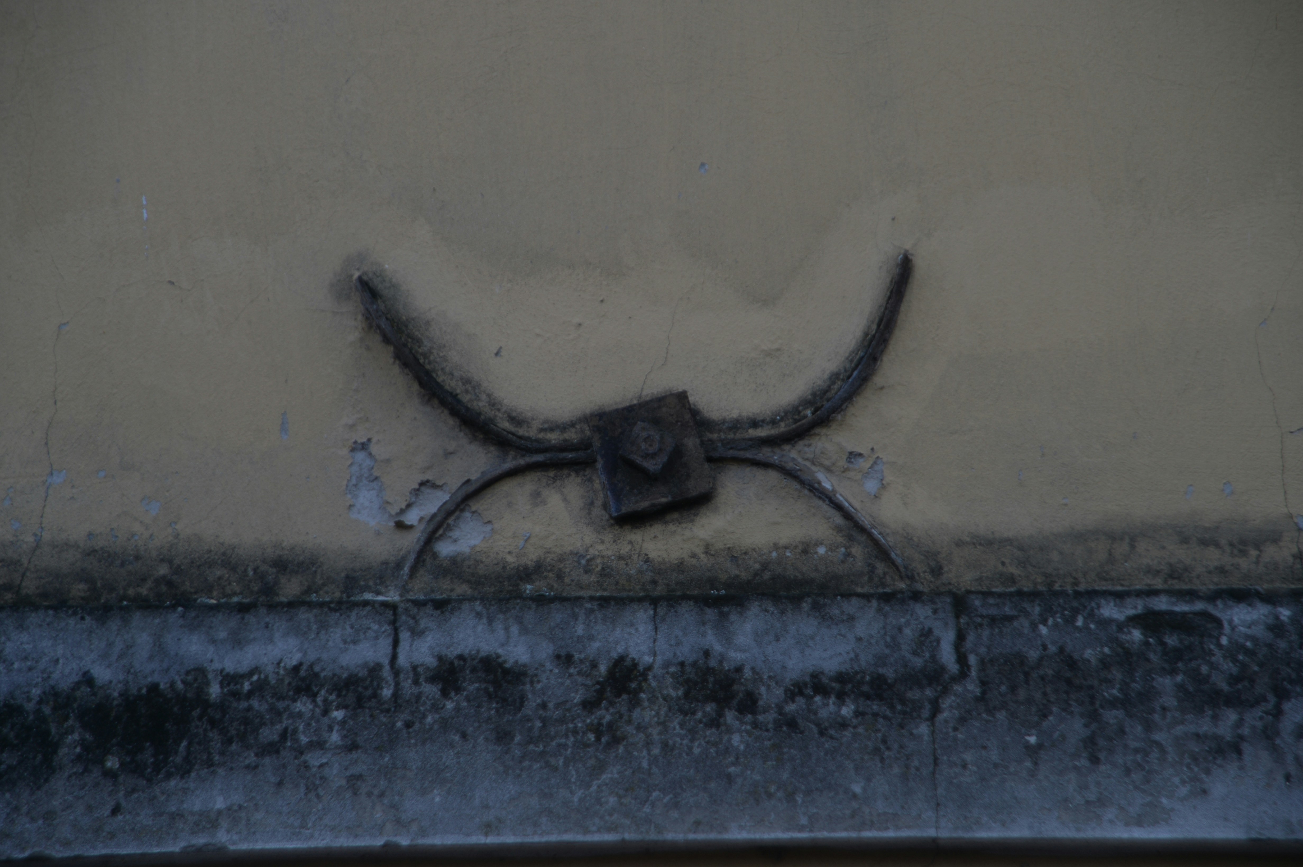 Crescent Iron Hook Anchored in a Weathered Wall