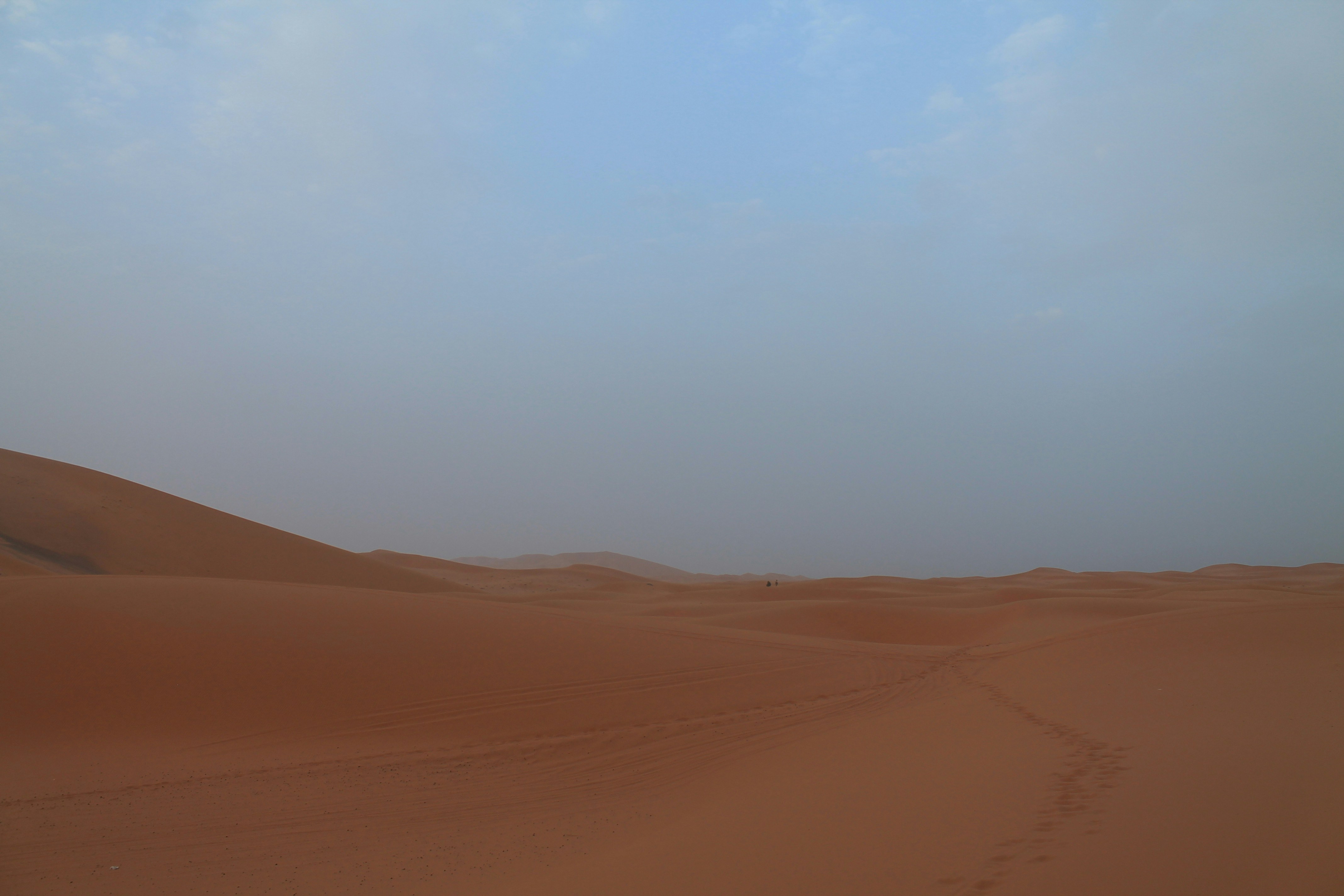 A person walking across a sandy field in the desert photo – Free Grey ...