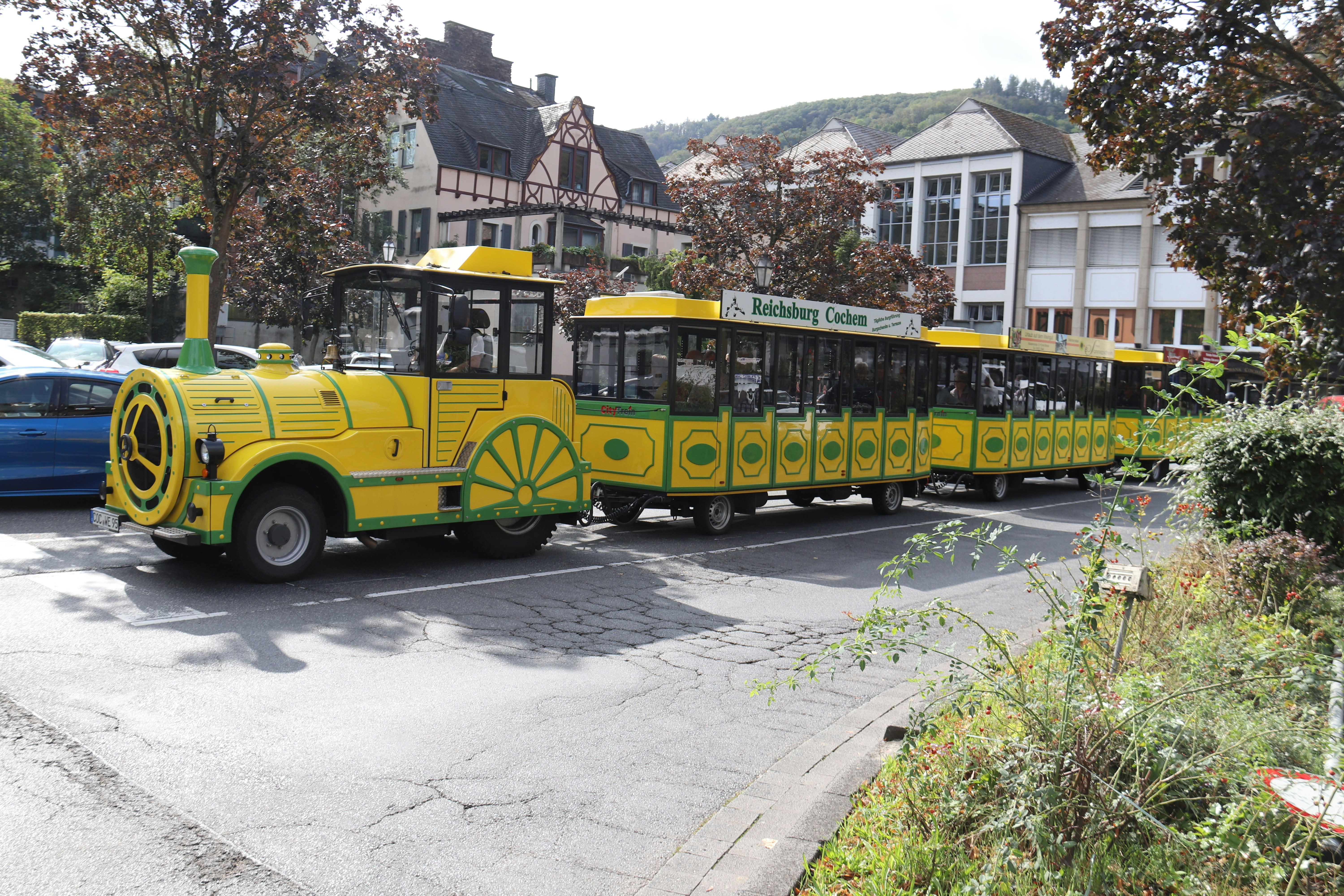 Lively green-and-yellow tourist train parked along an historic street