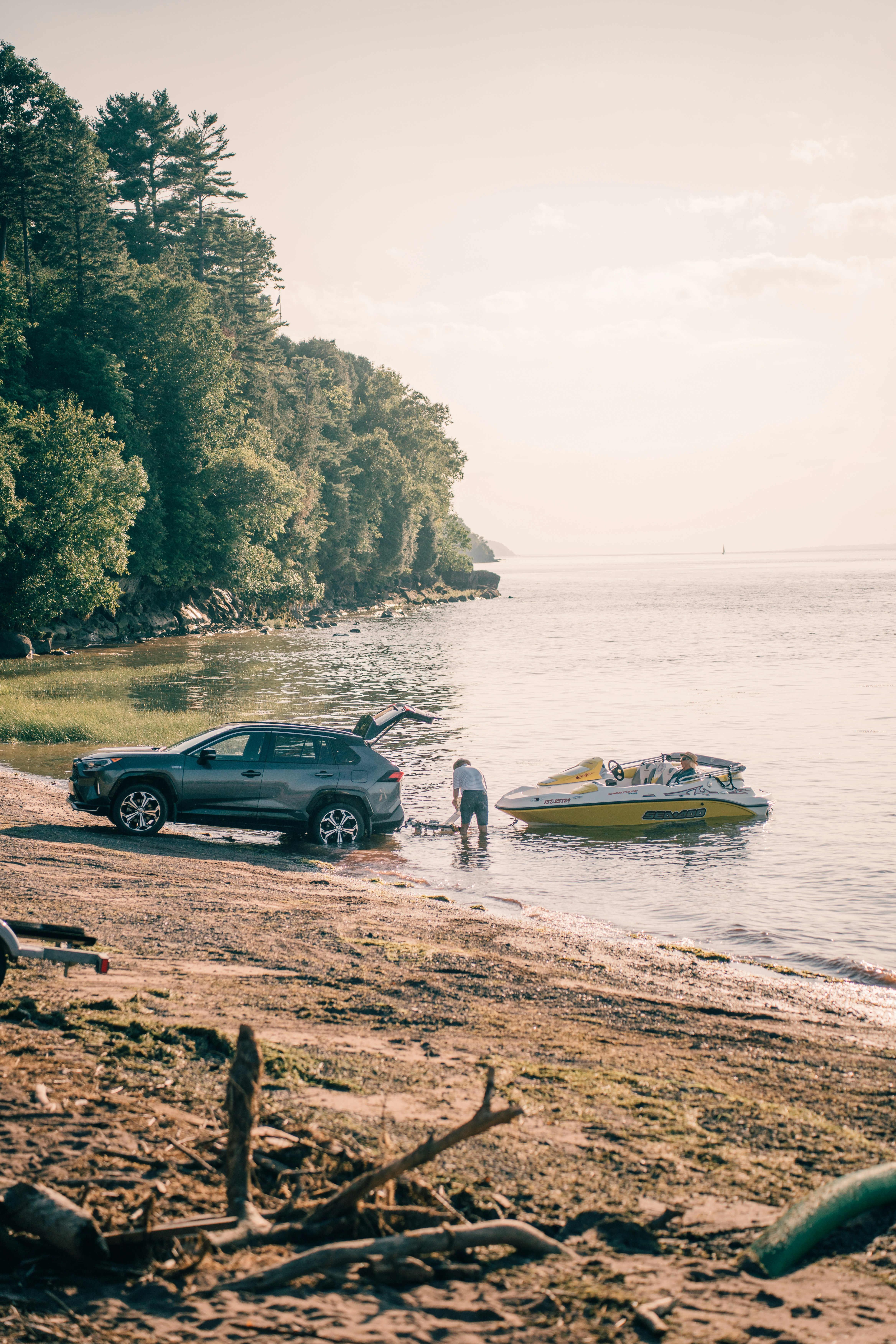 Shoreline Convergence: SUV, Boat, and a Solitary Figure at Golden Hour